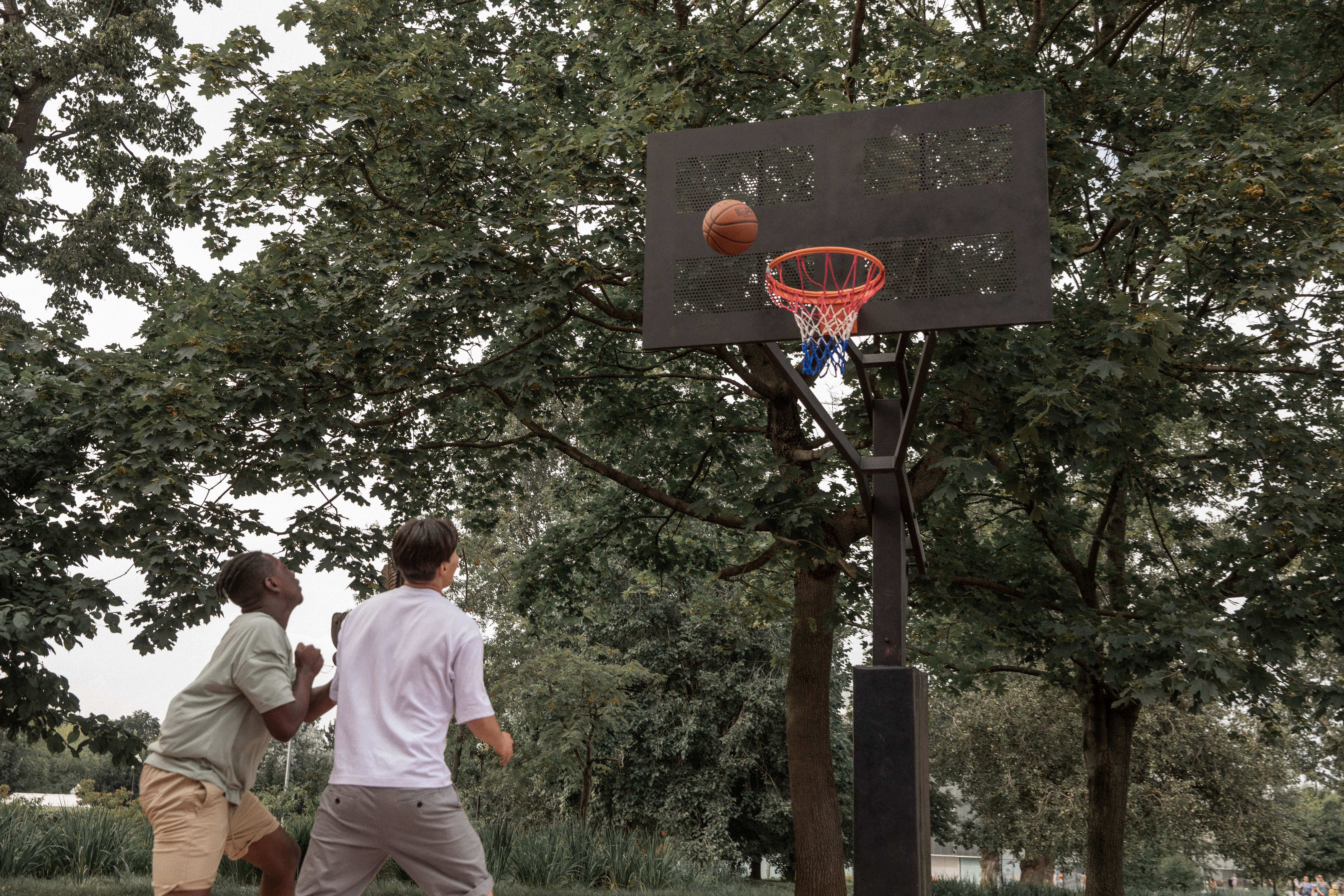 Faceless anonymous men playing basketball in park · Free Stock Photo