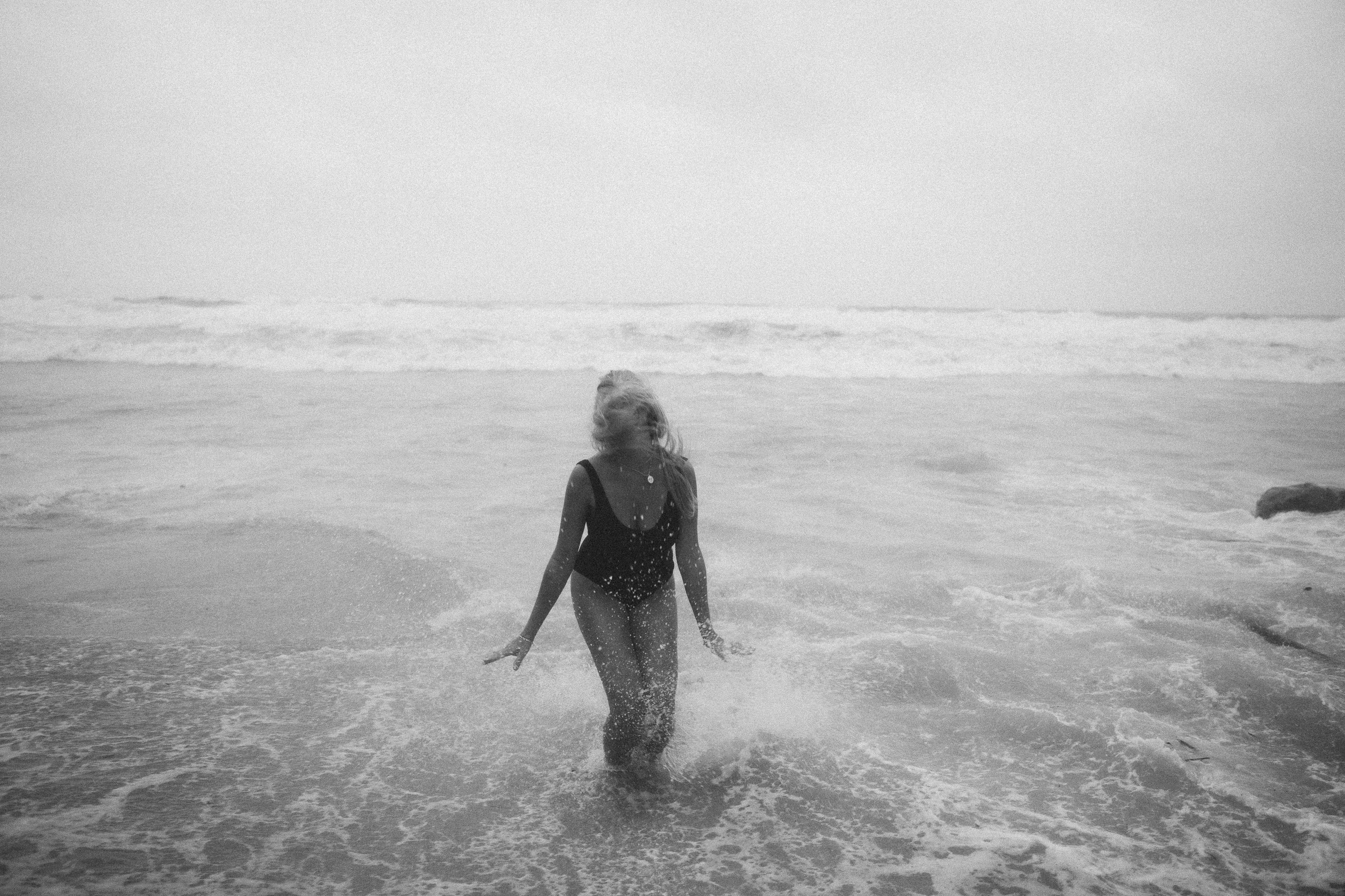 Woman in Swimsuit Splashing Water on Ocean Shore · Free Stock Photo