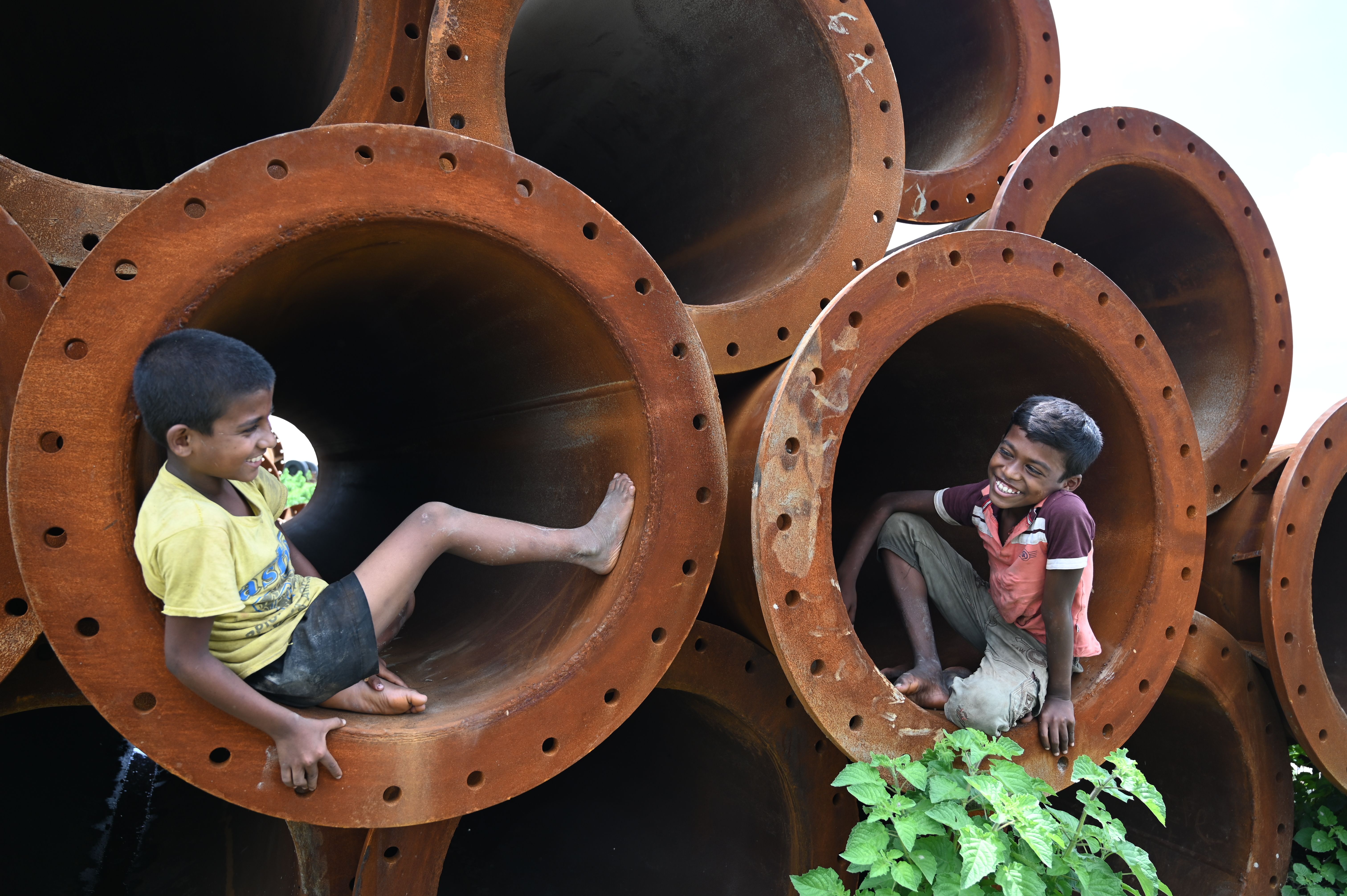 Boys Sitting in Huge Brown Steel Pipes · Free Stock Photo