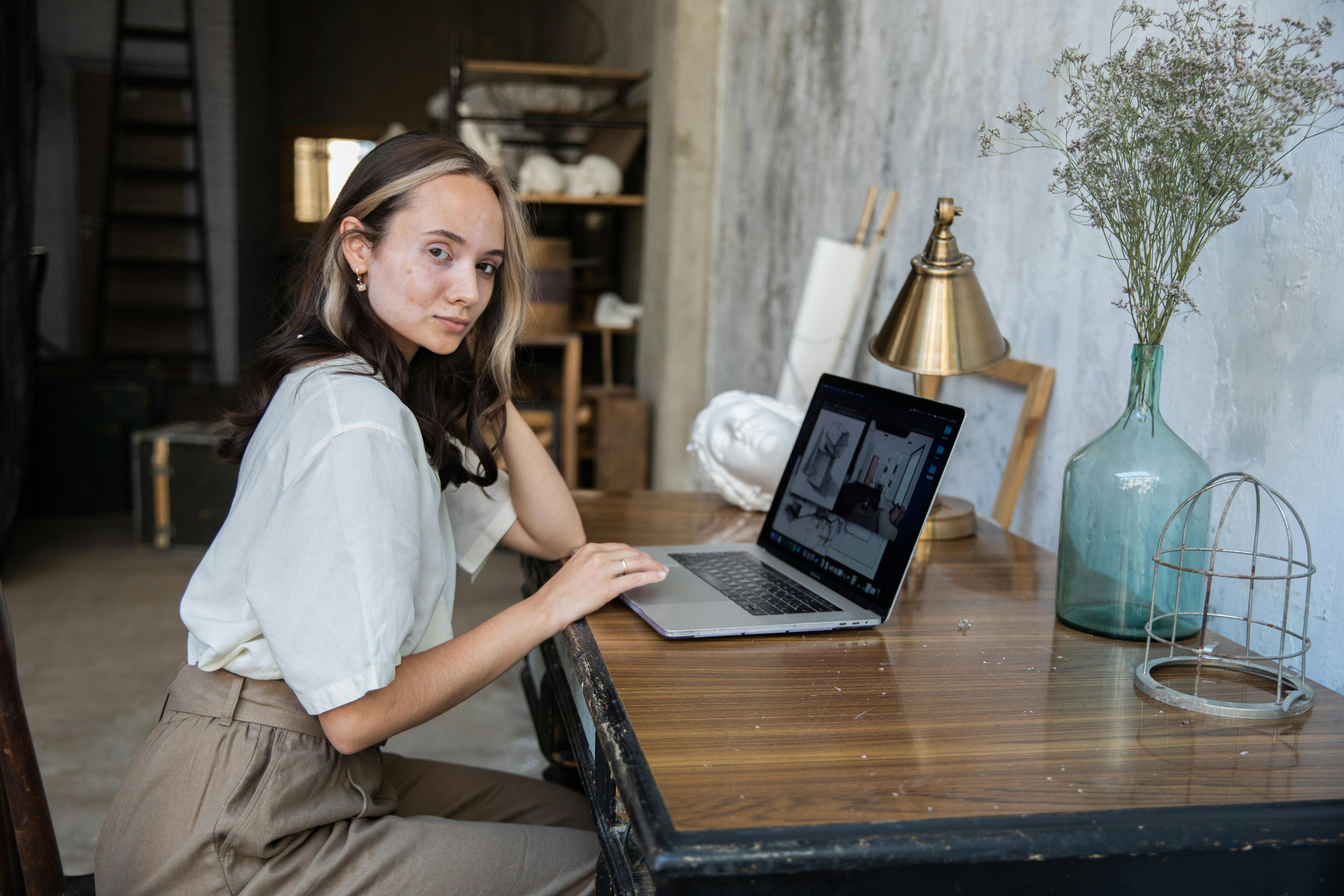 Woman in White Top Using Her Macbook on Wooden Table · Free Stock Photo