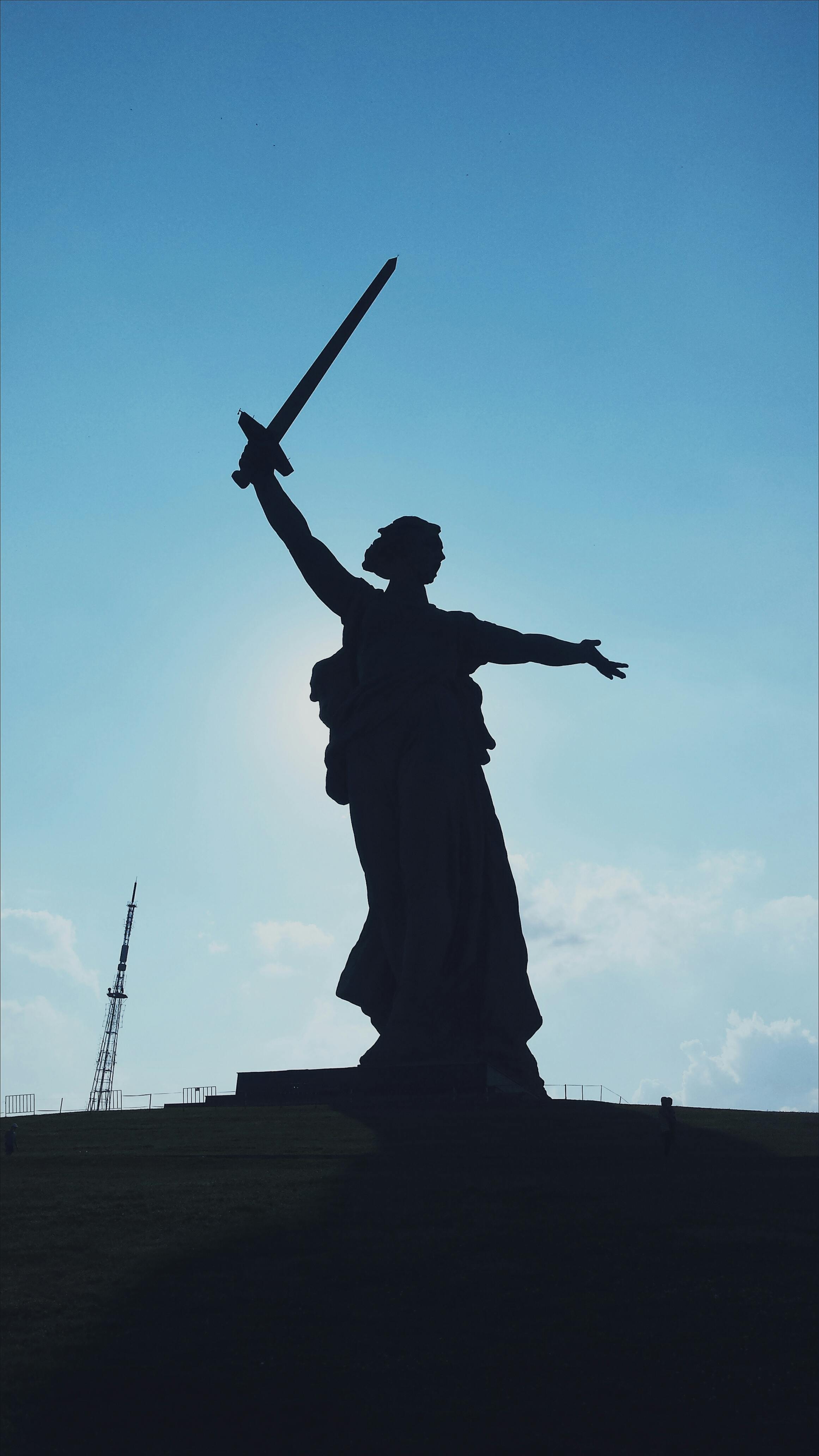 Silhouetted Statue of Woman Holding Sword · Free Stock Photo