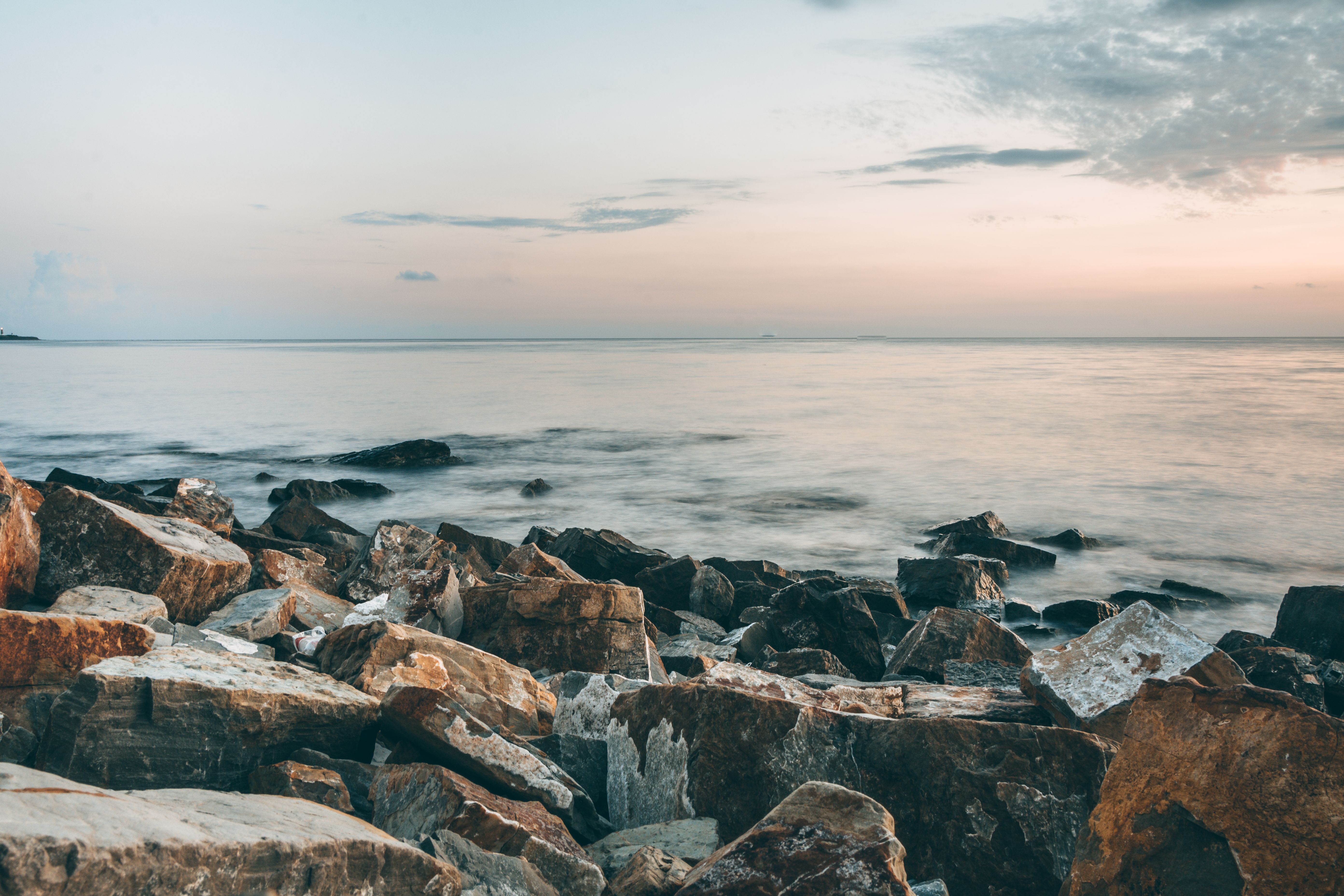 Rocky beach against wavy ocean under cloudy sky in twilight · Free ...