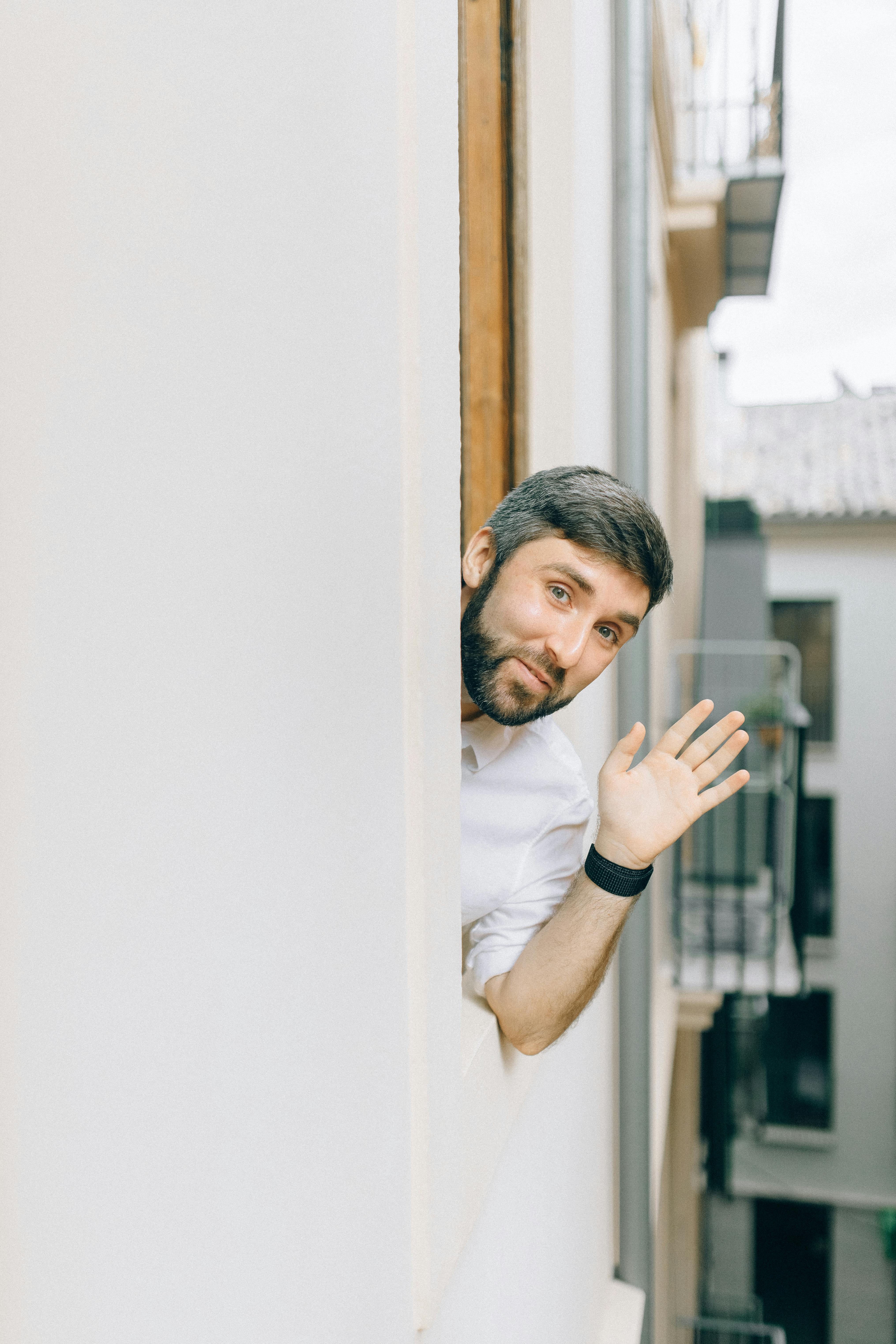 Man Poking Out His Head Out of Window Waving Hand · Free Stock Photo