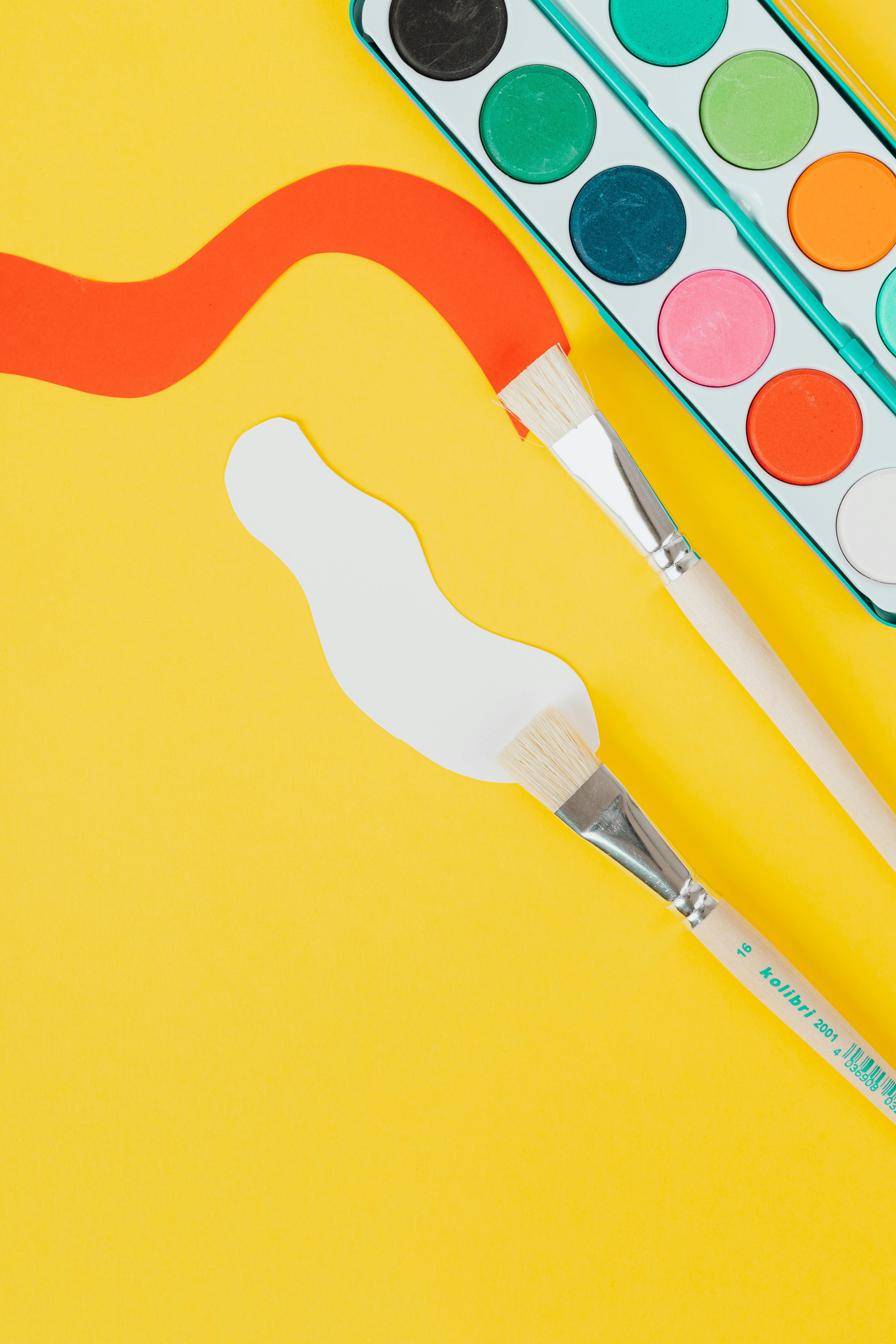Poster Paint Kit and Paint Brushes on Yellow Background · Free Stock Photo