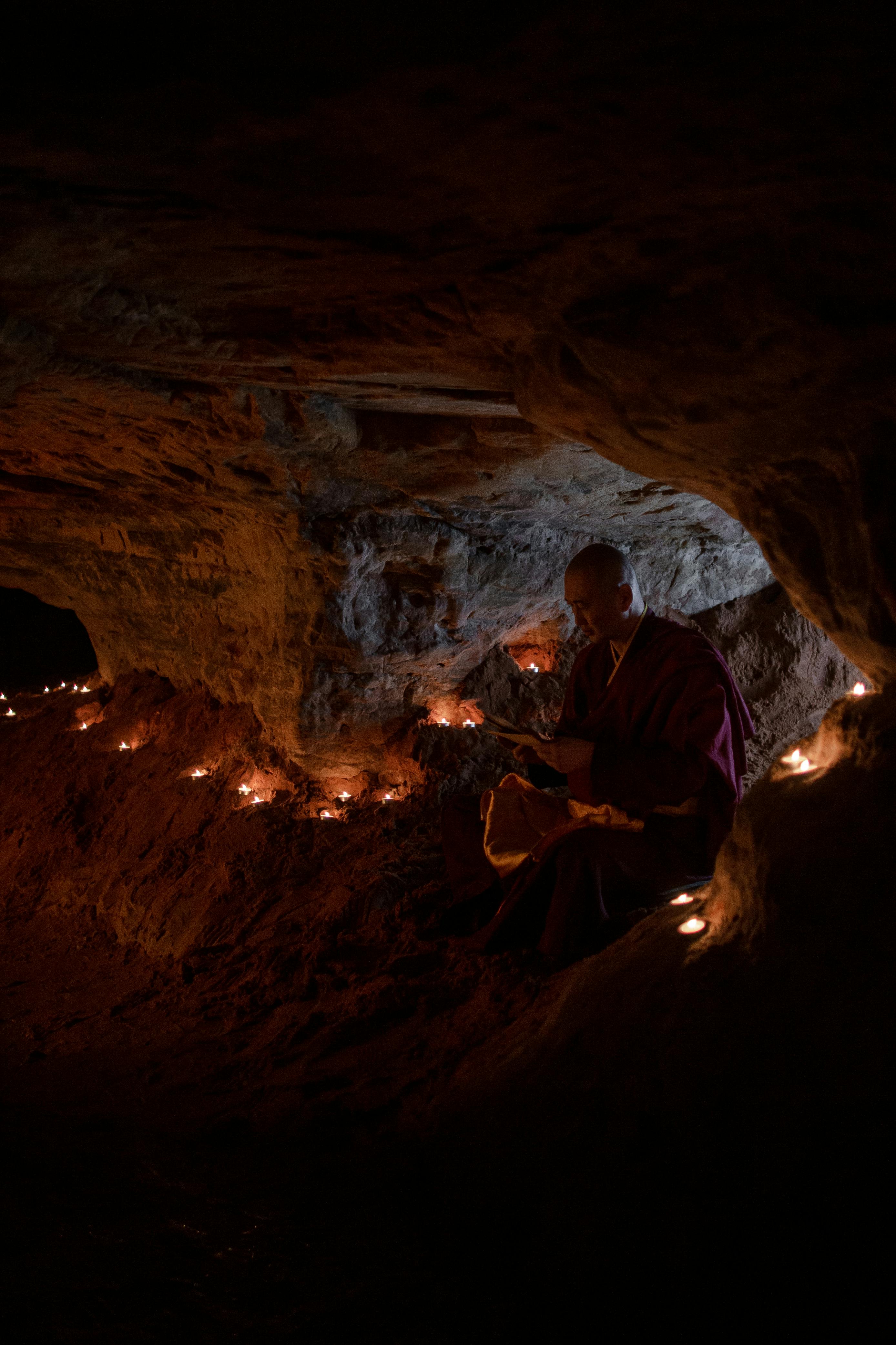 Buddhist Monk in a Cave Reading by Candlelight · Free Stock Photo