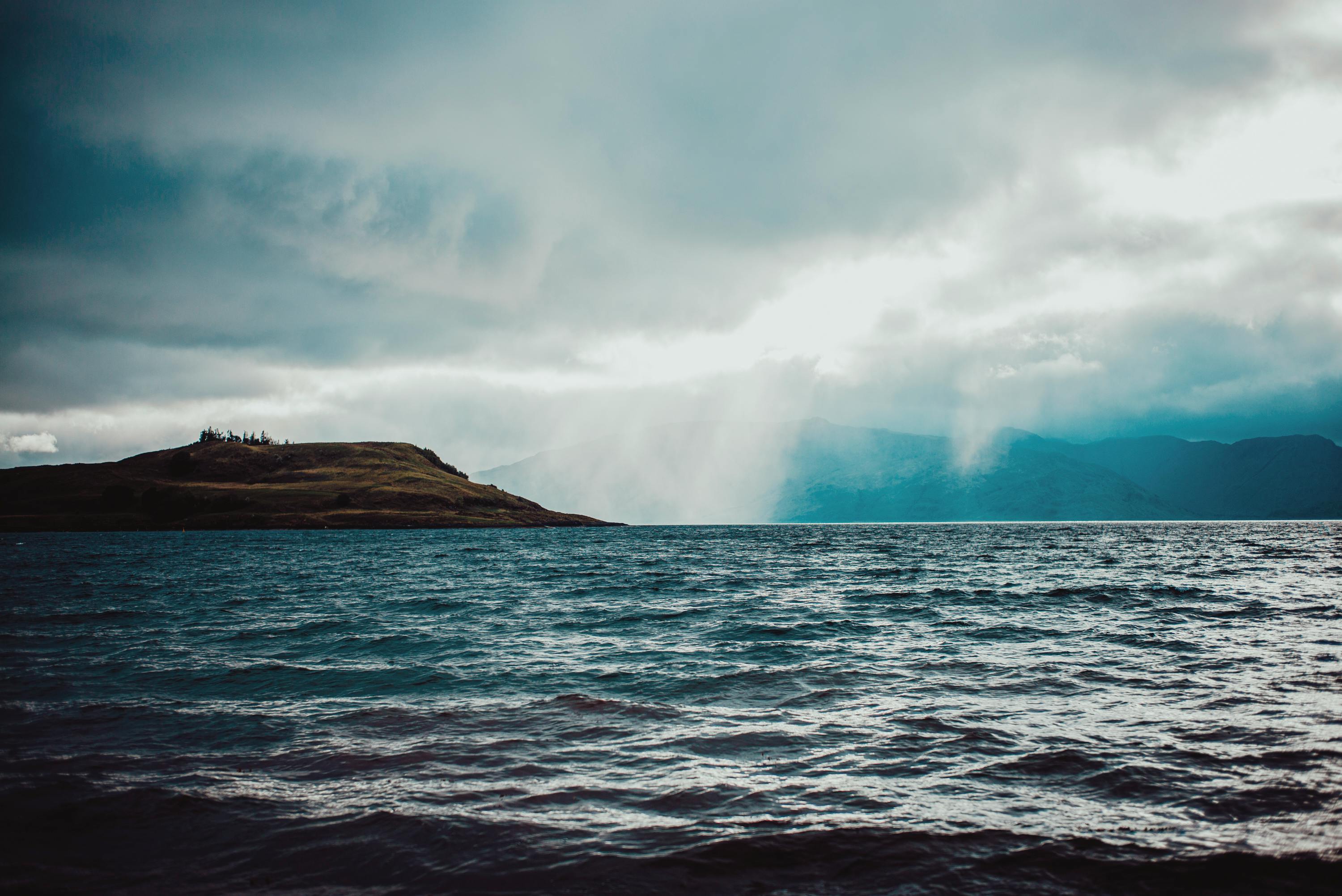 Wavy ocean with rocky island in rainy weather · Free Stock Photo