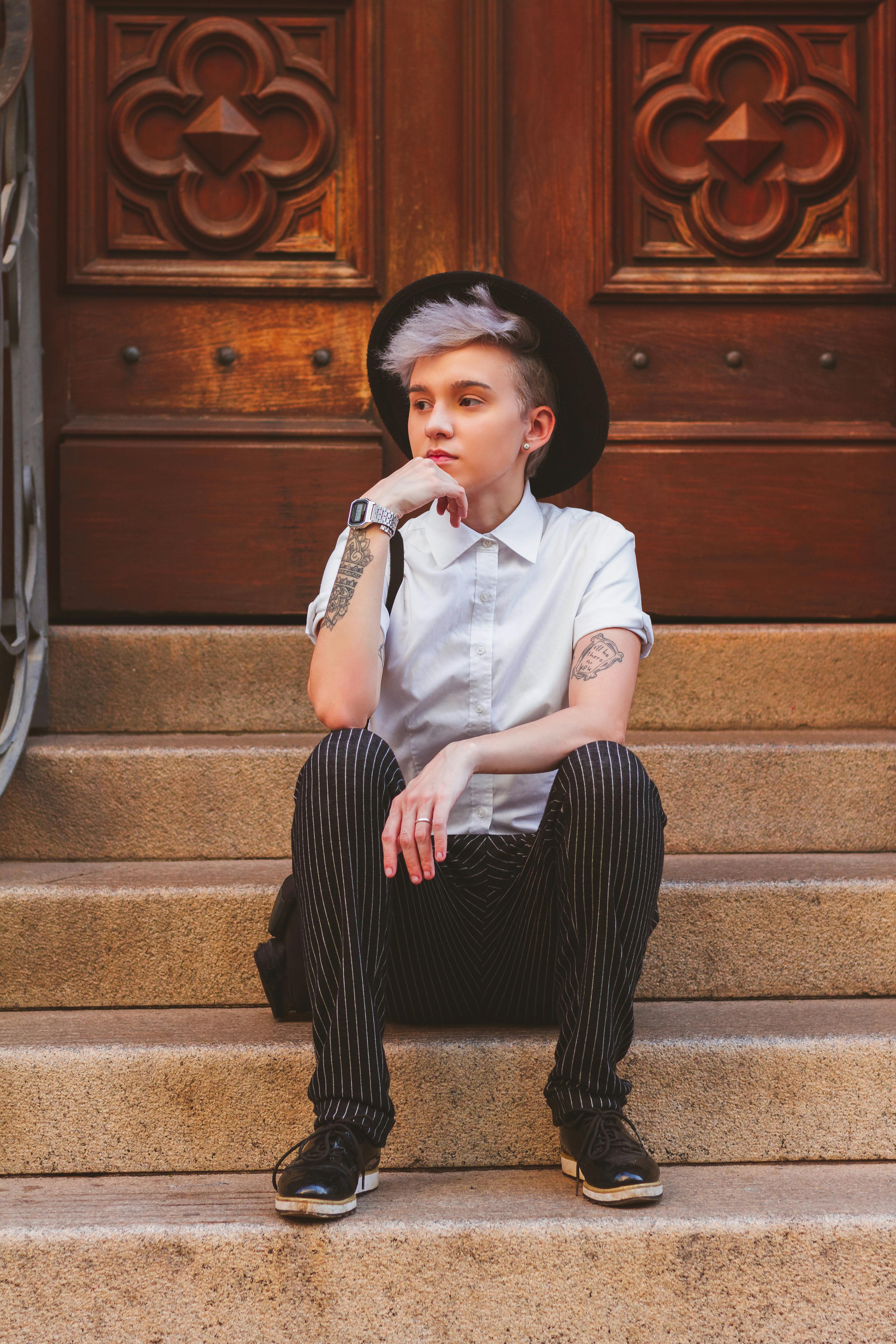 Portrait of Person Wearing Fedora Sitting on Steps · Free Stock Photo