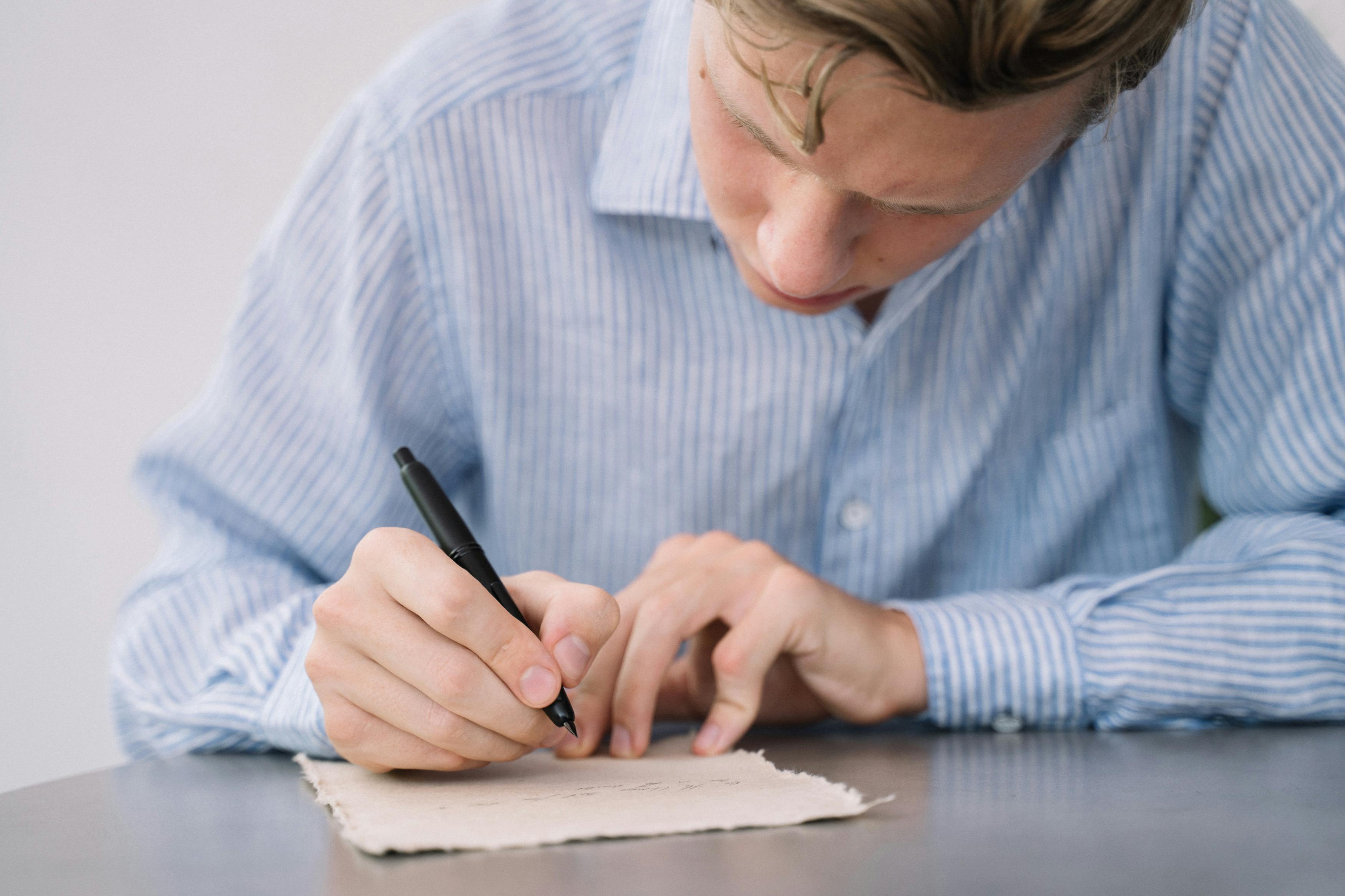 Man in Shirt Sitting and Writing on Paper · Free Stock Photo