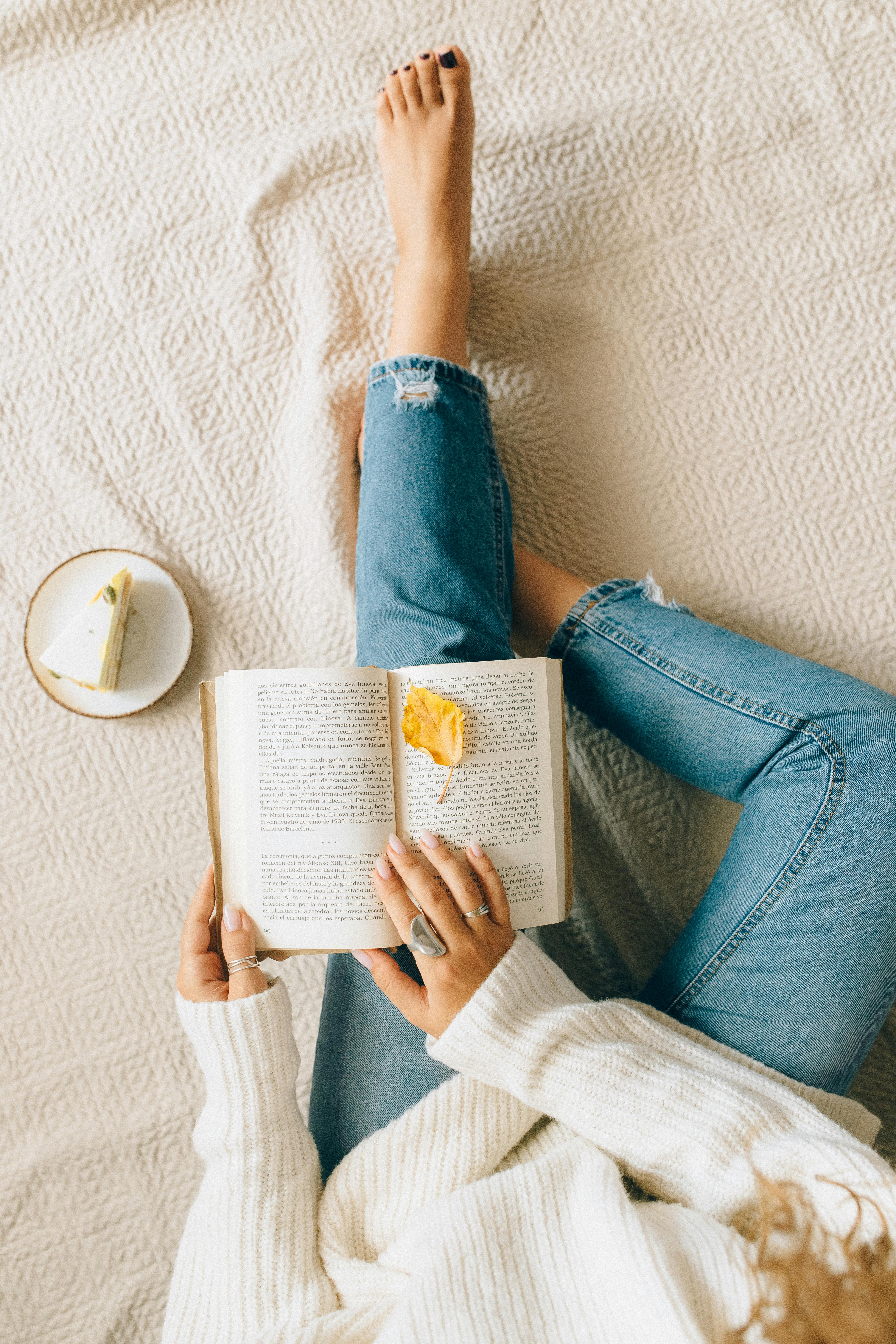Person in Blue Denim Jeans Reading Book · Free Stock Photo