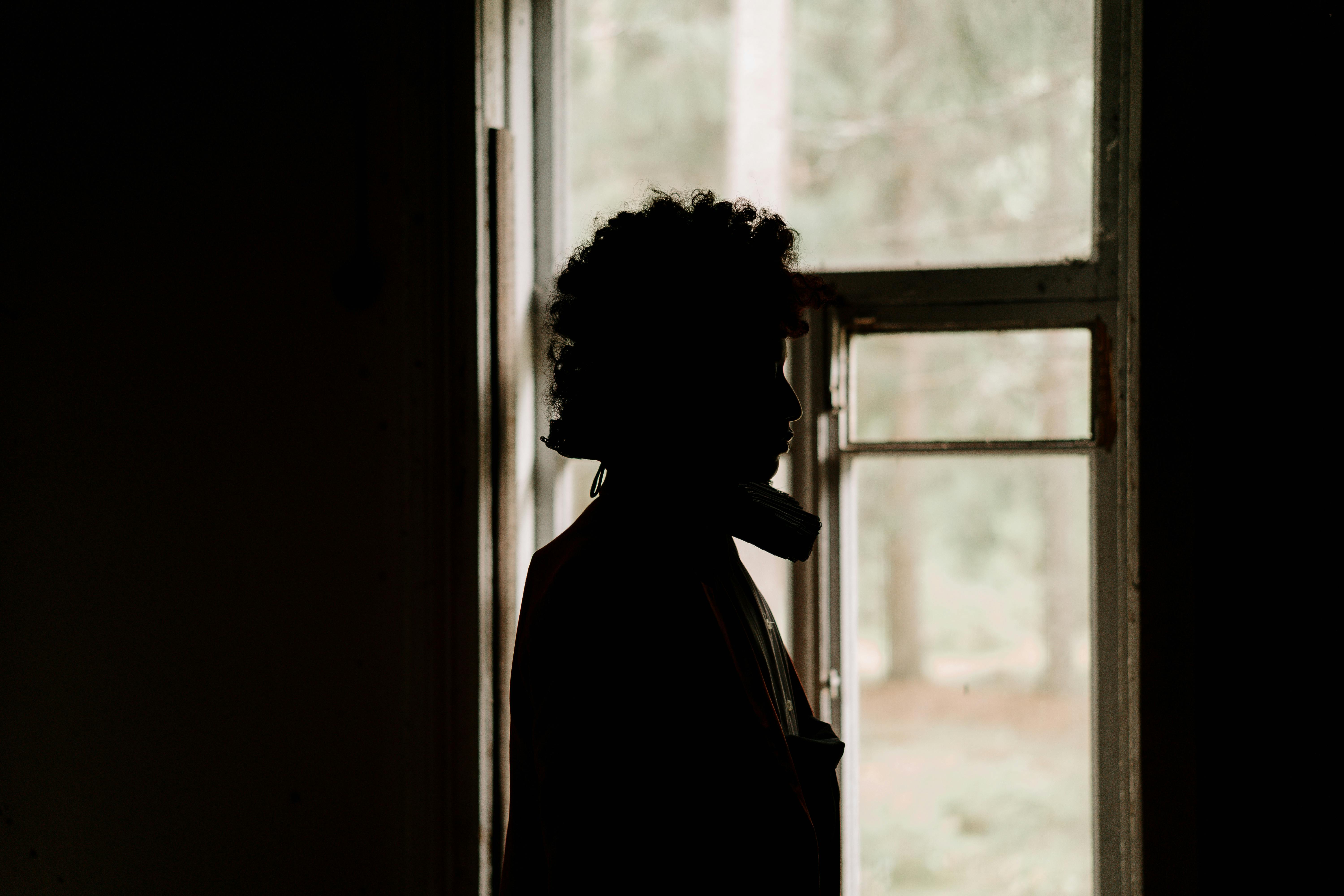 Silhouette of Person Standing Near Window · Free Stock Photo