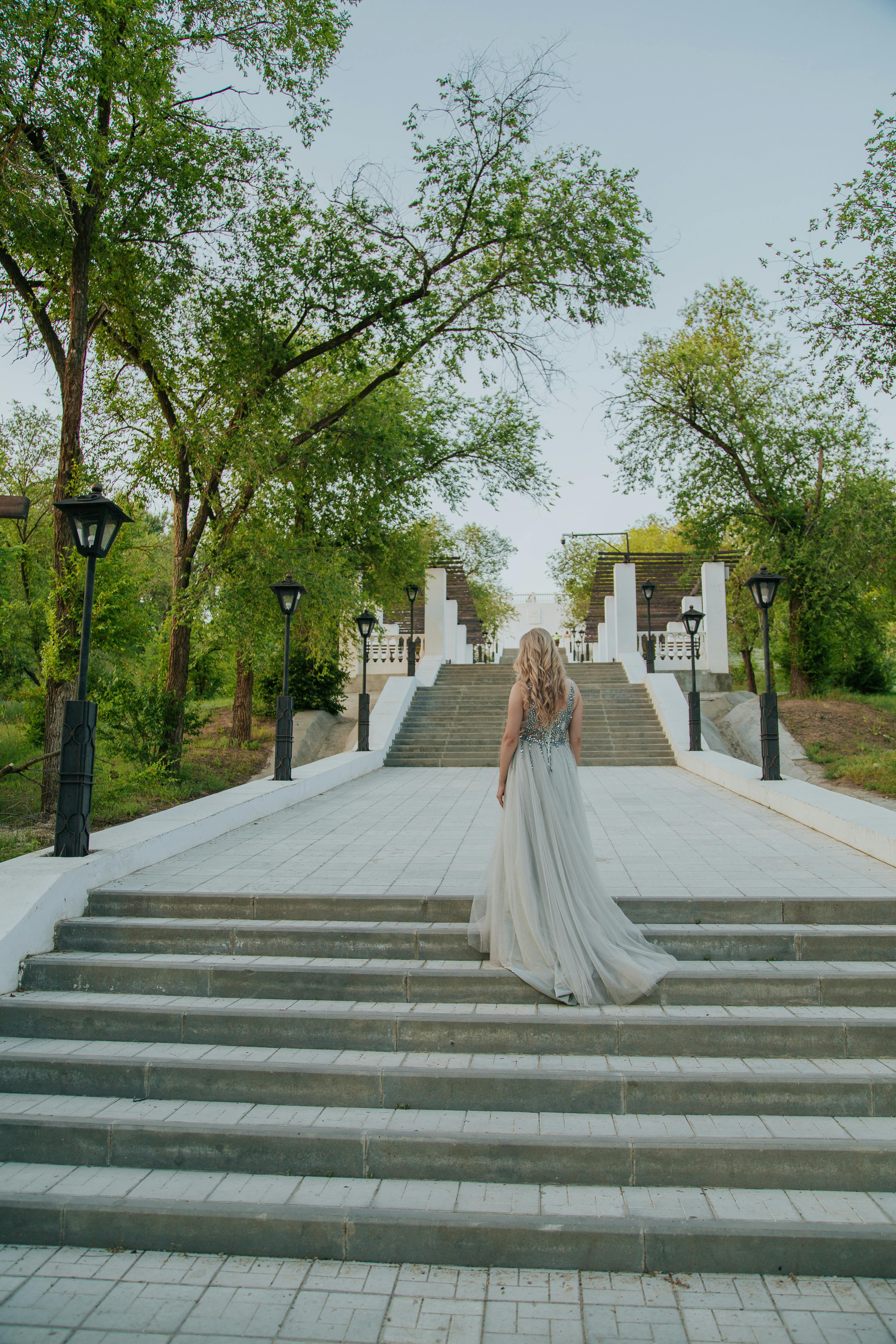 Woman wearing long bridal dress standing on stairs · Free Stock Photo