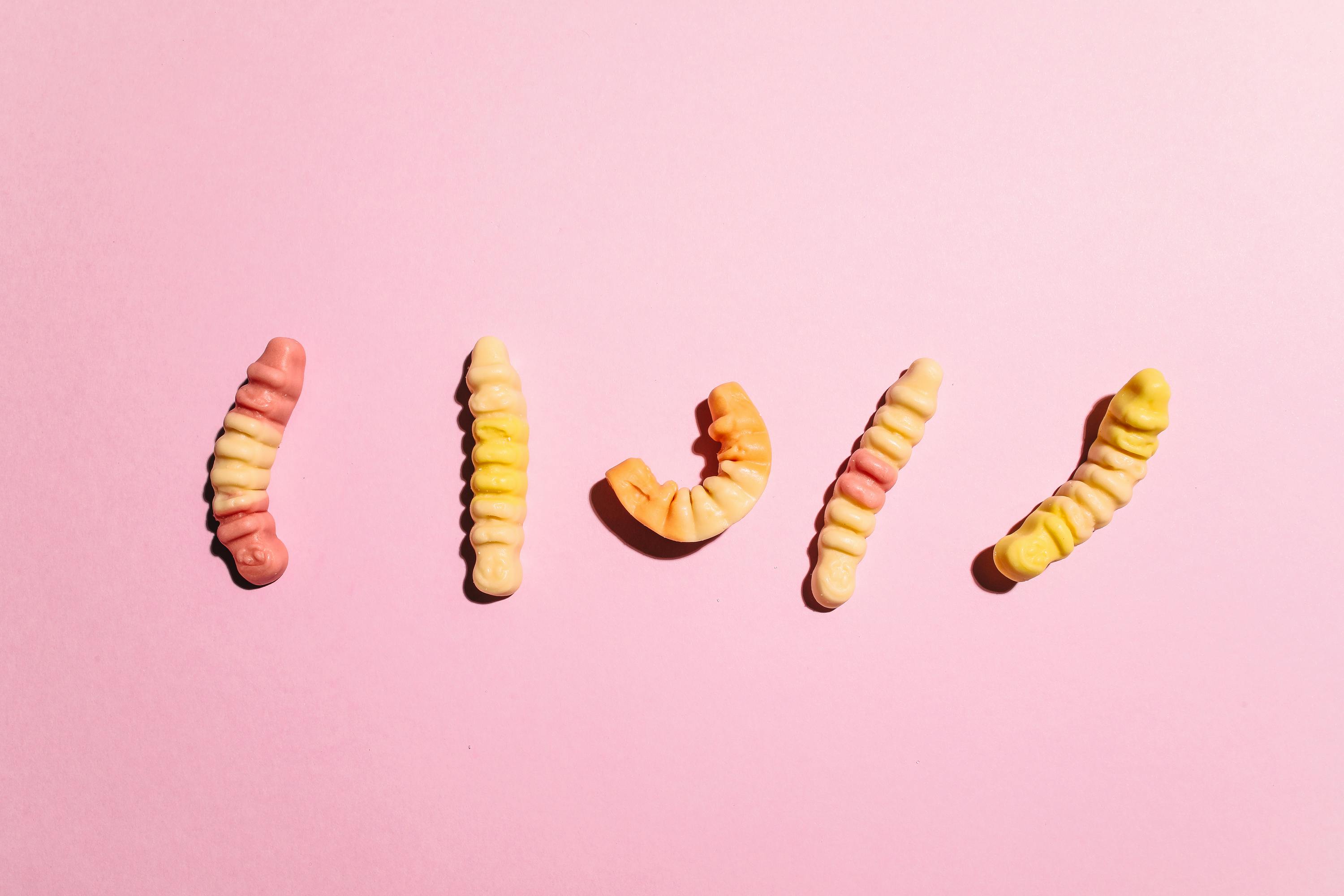 Close-Up Shot of Gummy Worms on Pink Surface · Free Stock Photo