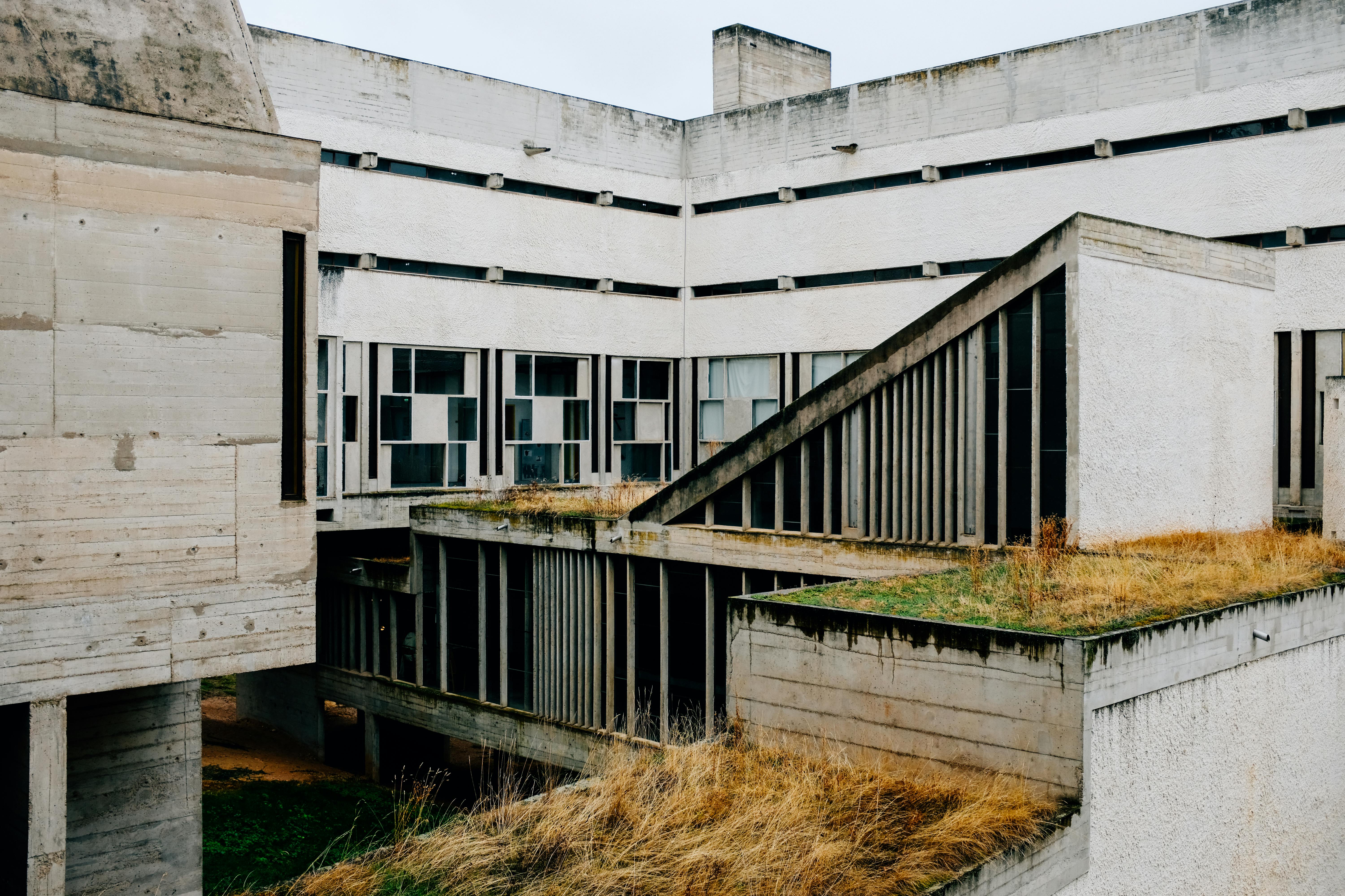 Old building facade with faded grass and weathered walls · Free Stock Photo
