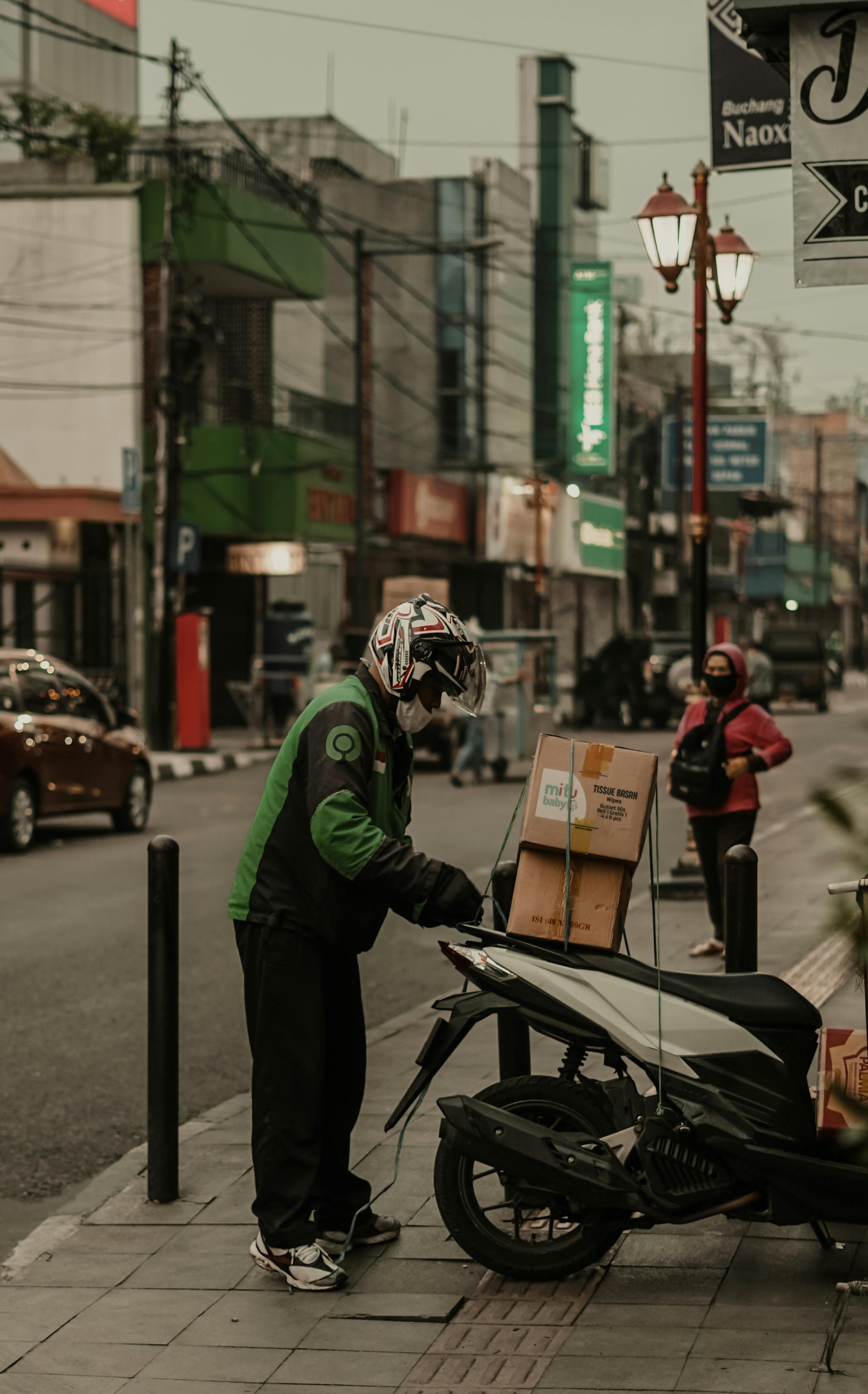 Motorcyclist tying Boxes on a Motor · Free Stock Photo