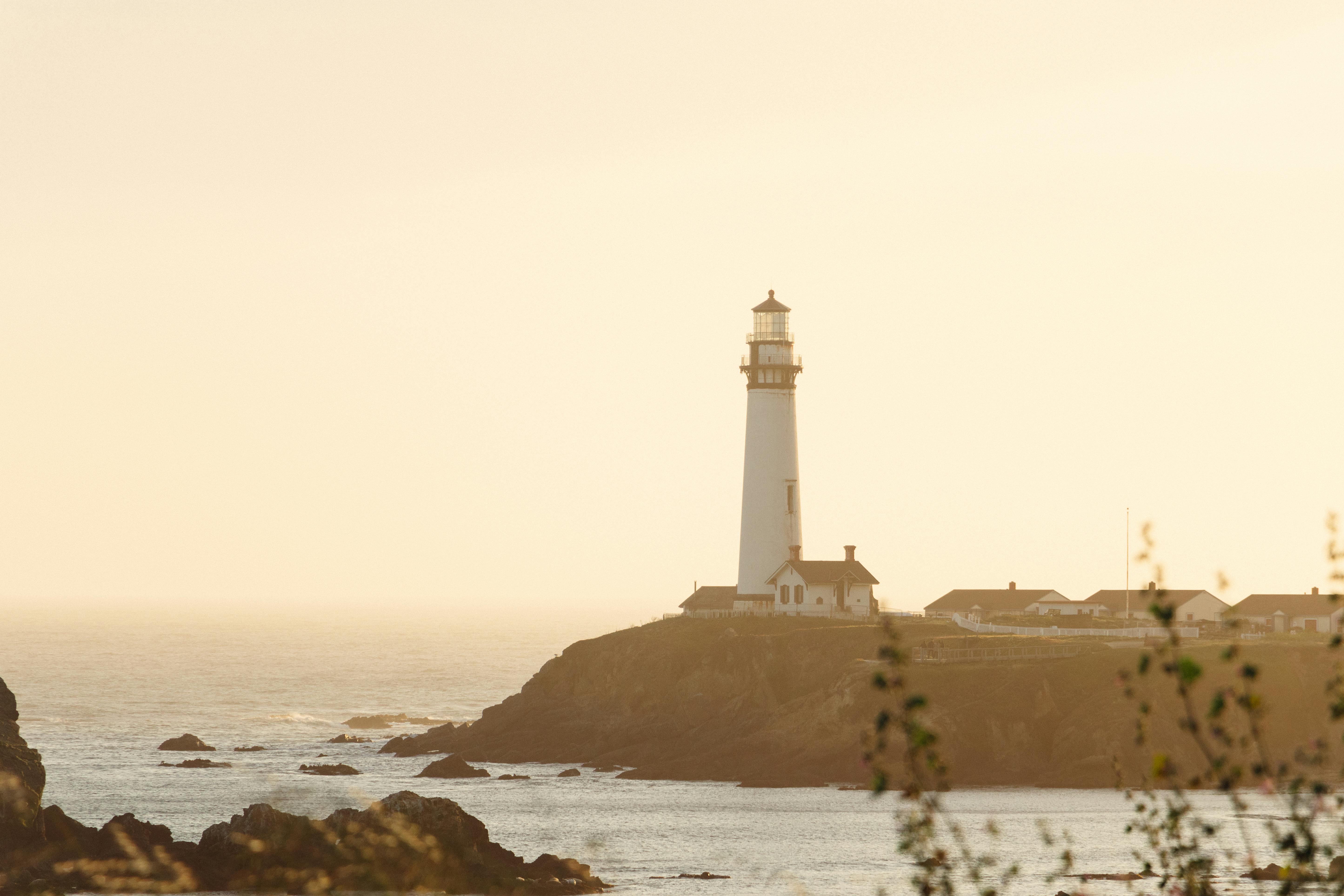 Lighthouse placed on rocky shore near ocean · Free Stock Photo