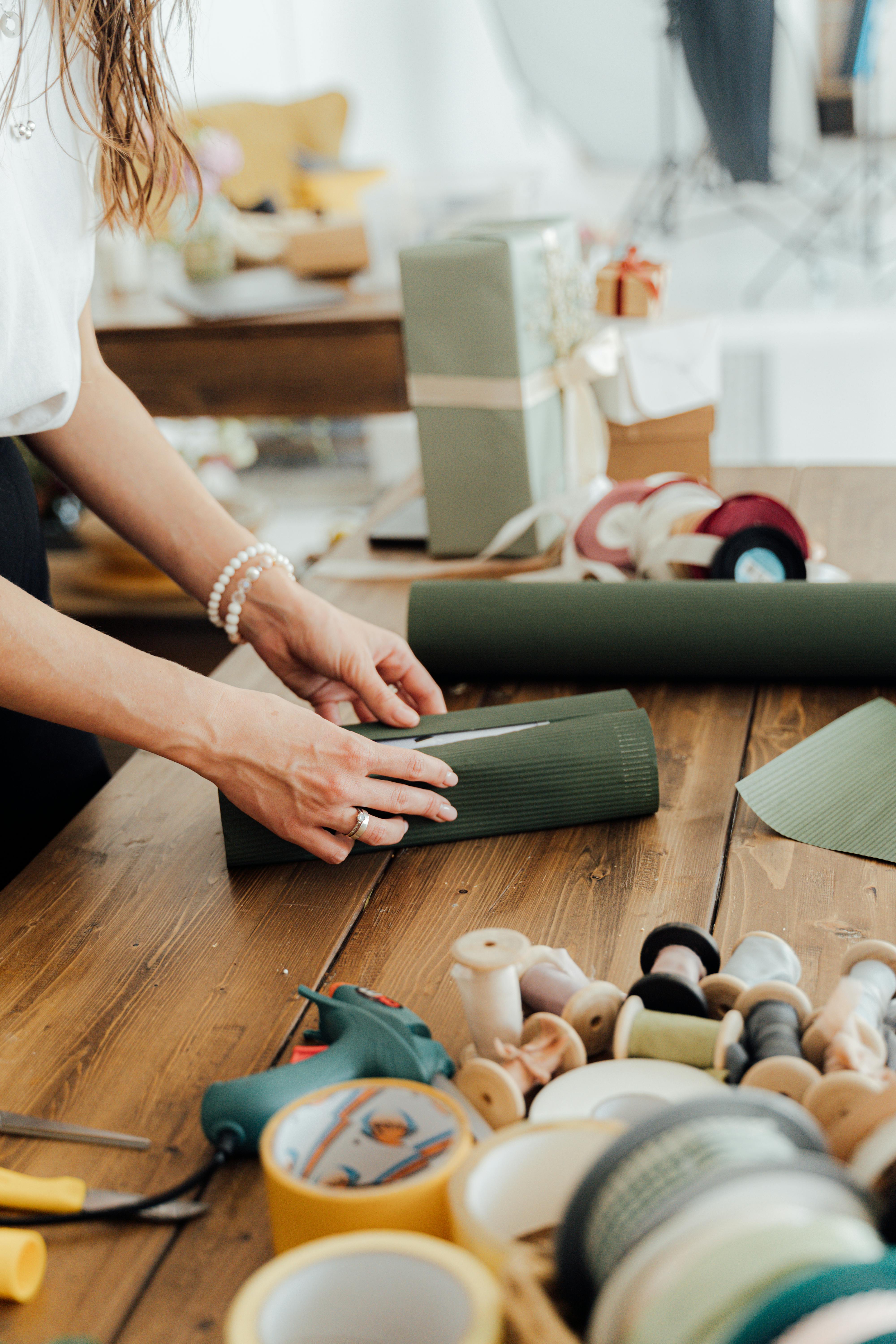 A Person Wrapping a Gift on a Wooden Table · Free Stock Photo