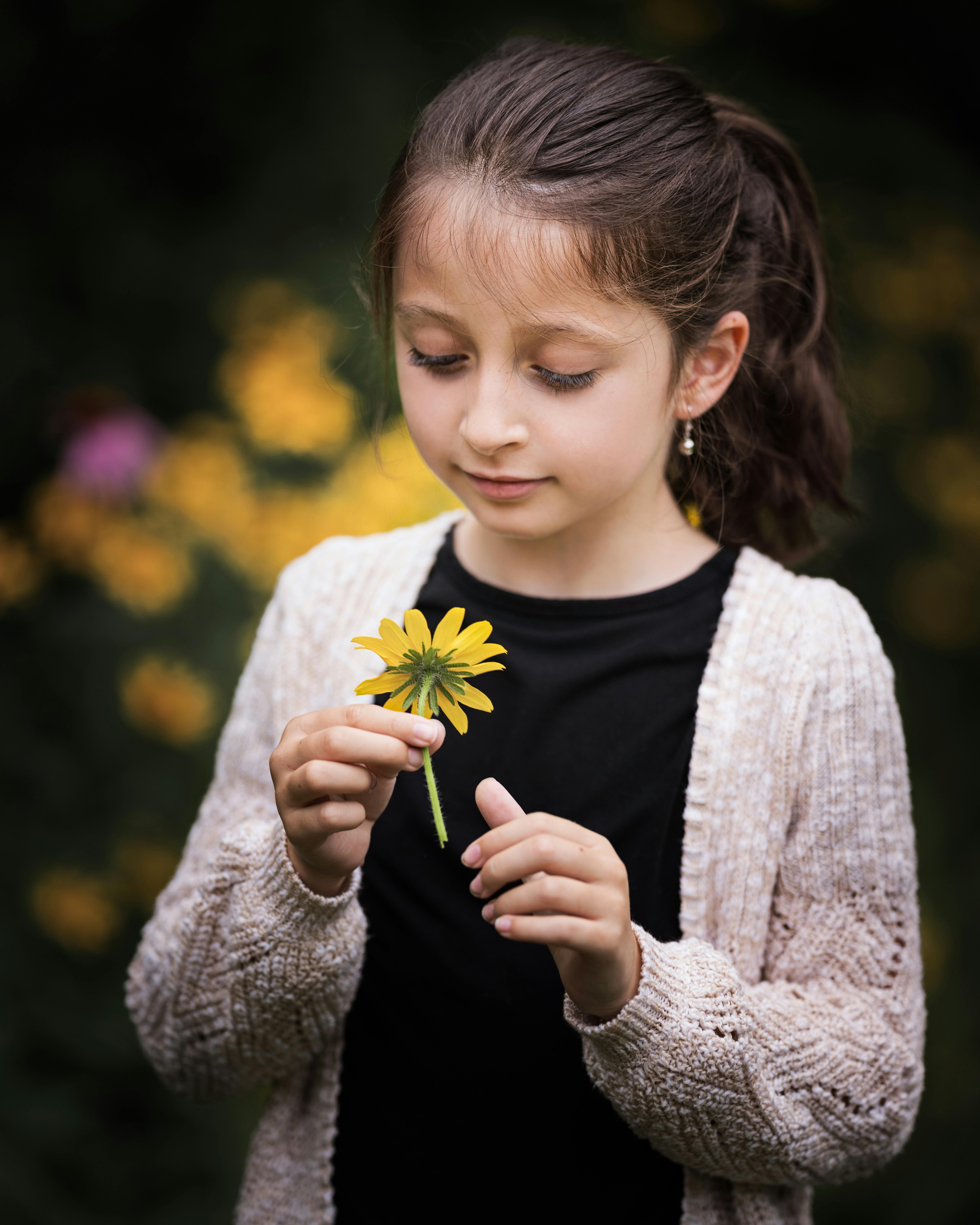 Adorable kid with yellow flower in hand resting in garden · Free Stock ...
