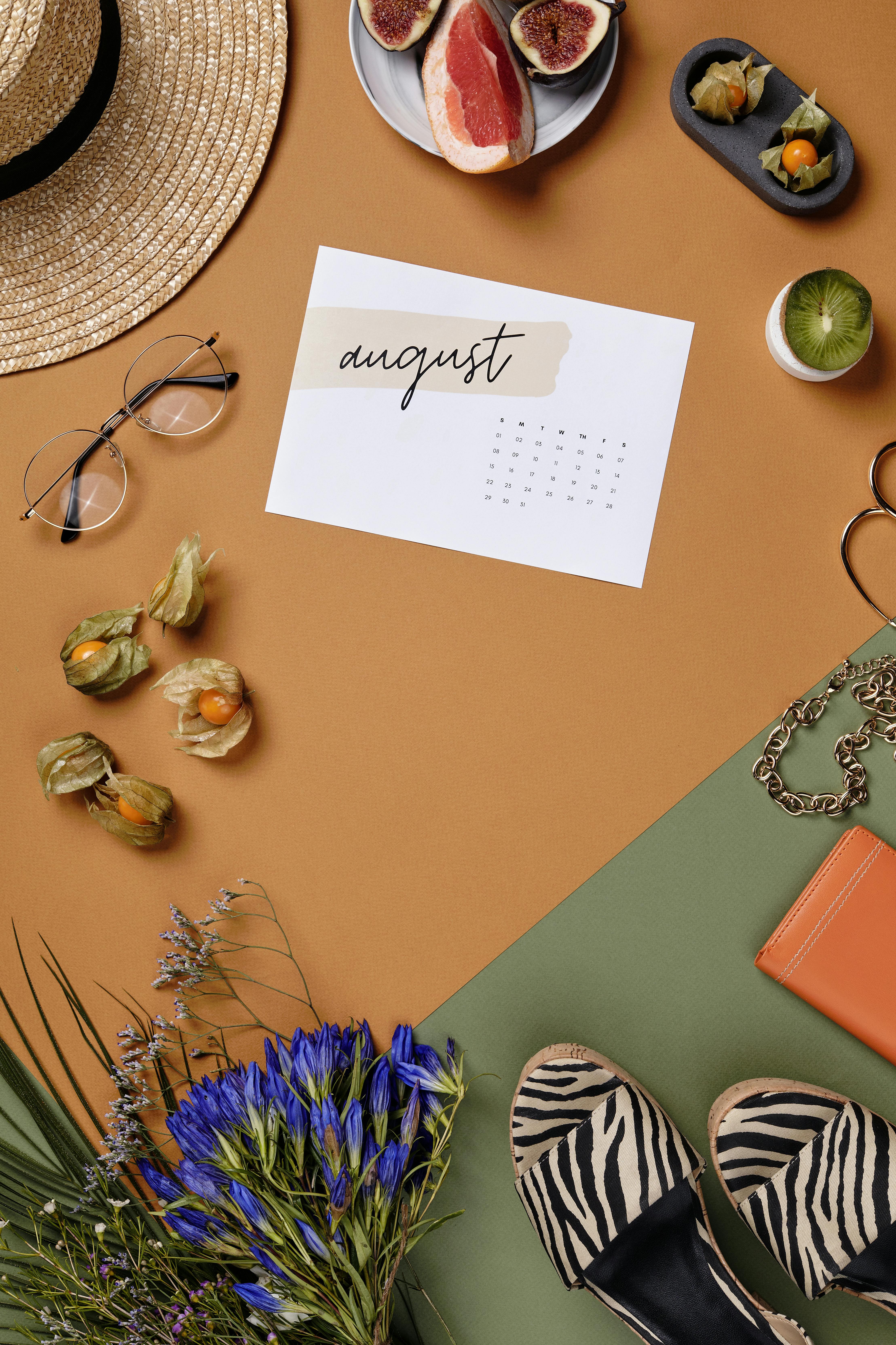 An August Calendar on Brown Surface Beside Eyeglasses · Free Stock Photo
