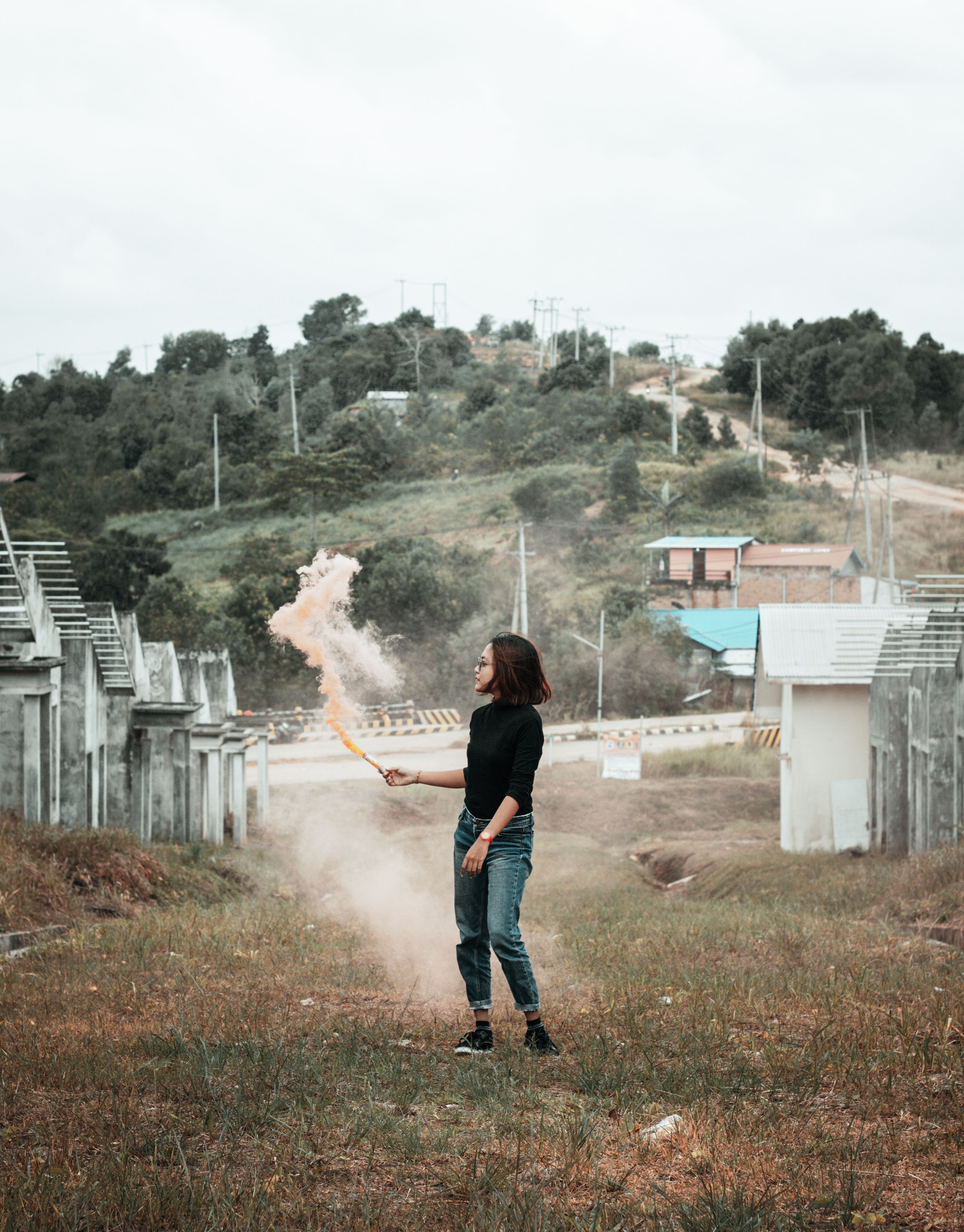 Woman Holding Flaming Flare Between Houses · Free Stock Photo