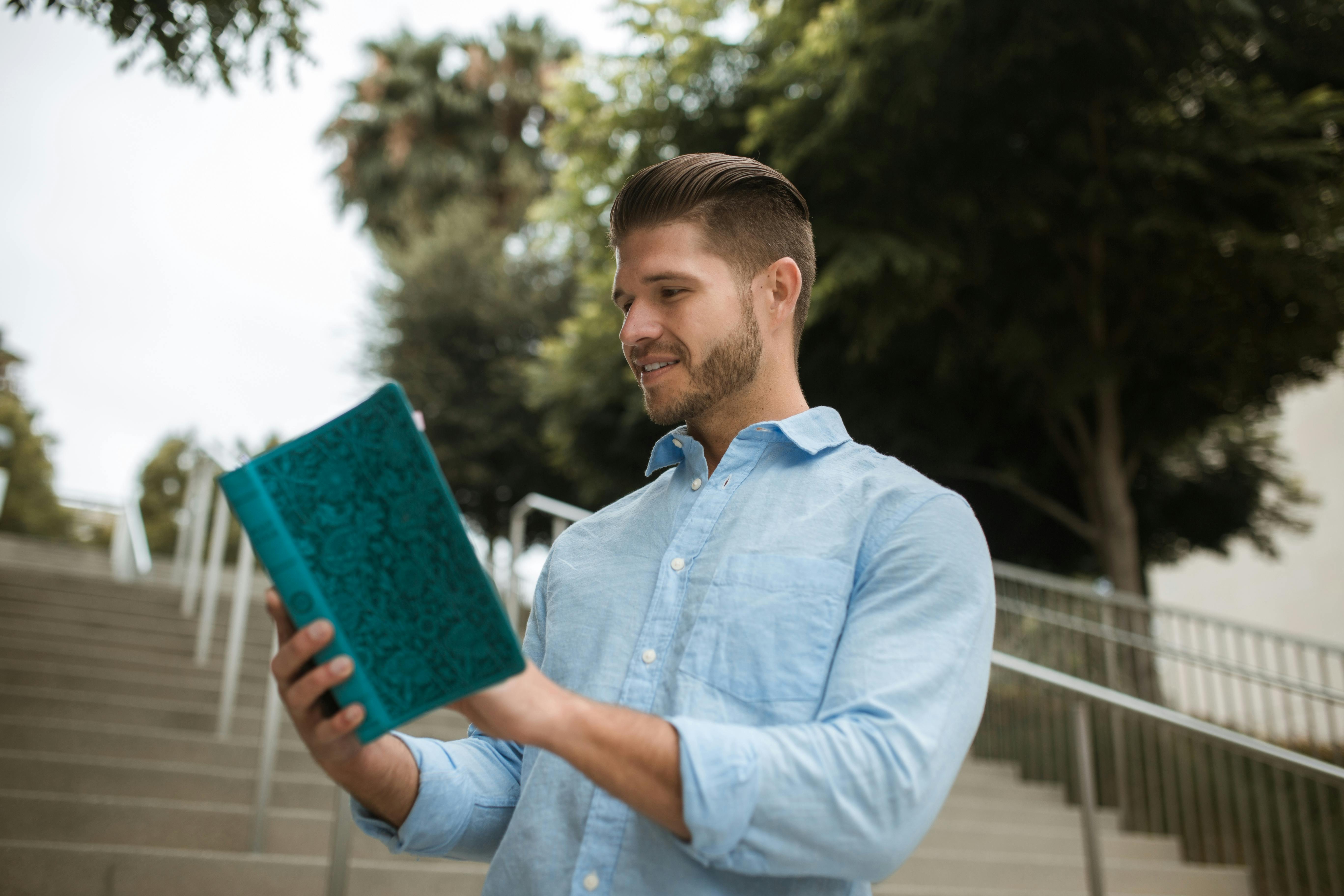 A Bearded Man in a Blue Long Sleeved Shirt Reading a Book · Free Stock ...