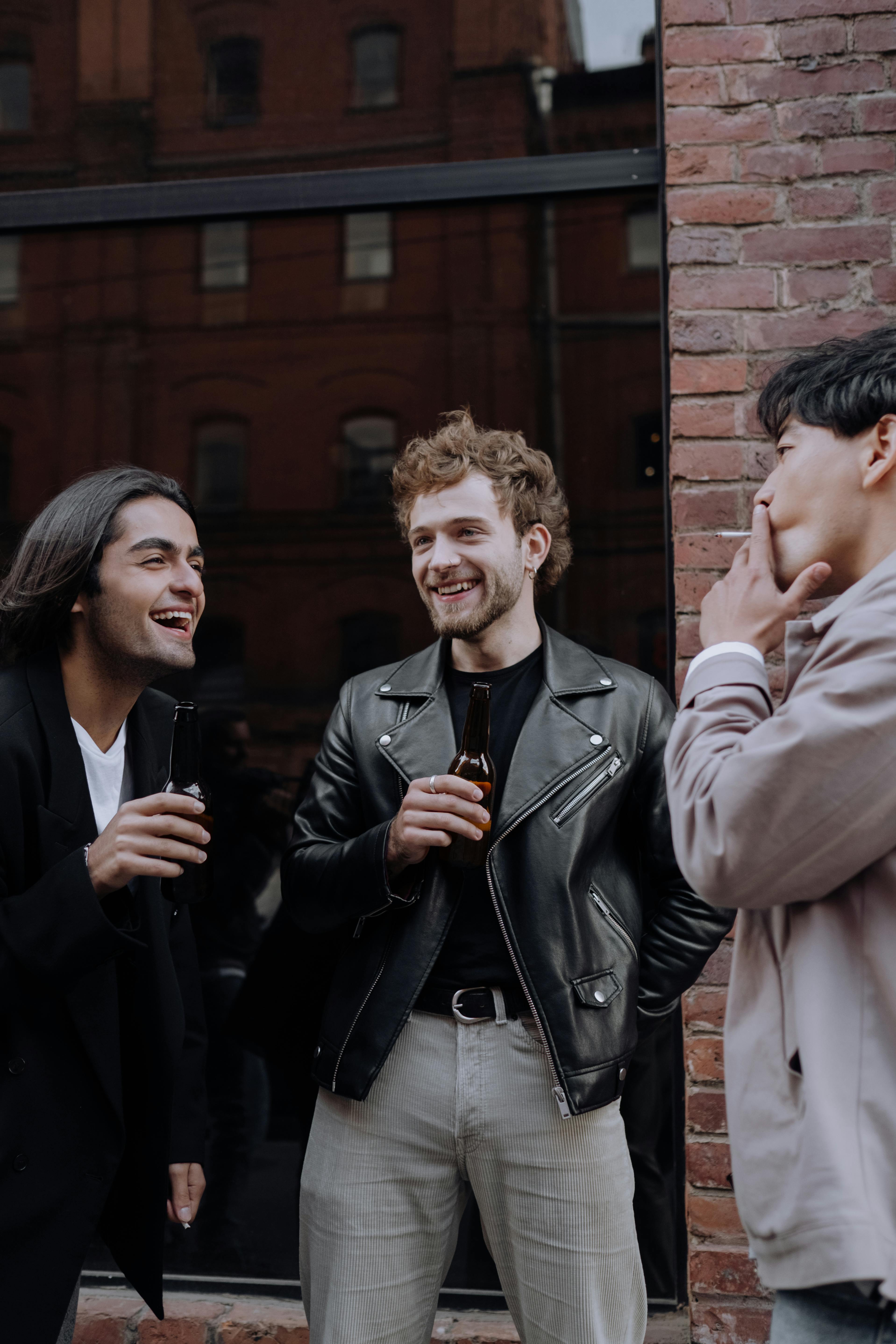Group of Friends Laughing while Holding Beer Bottles and Smoking ...