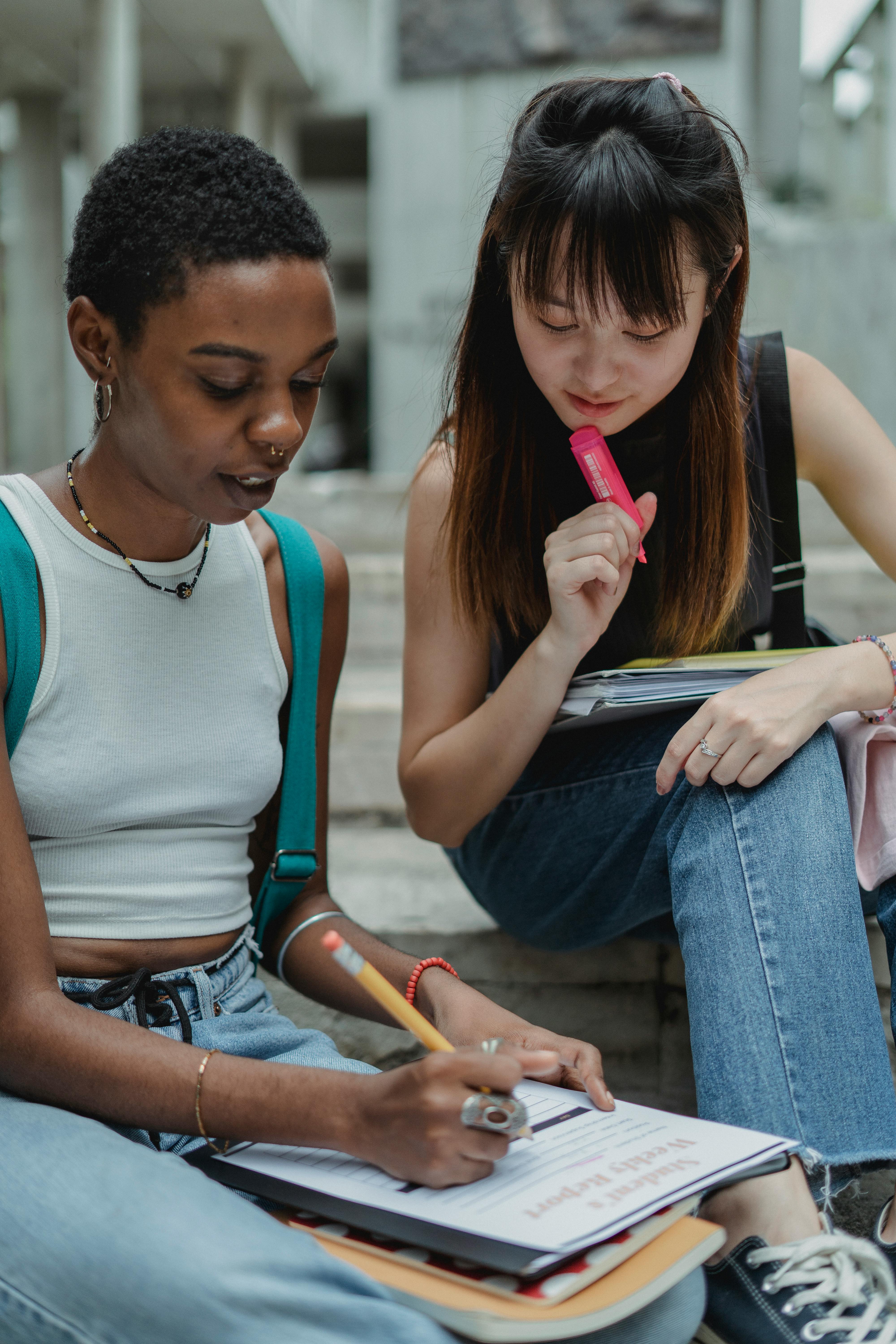 Serious multiethnic students sharing ideas for homework in city street ...