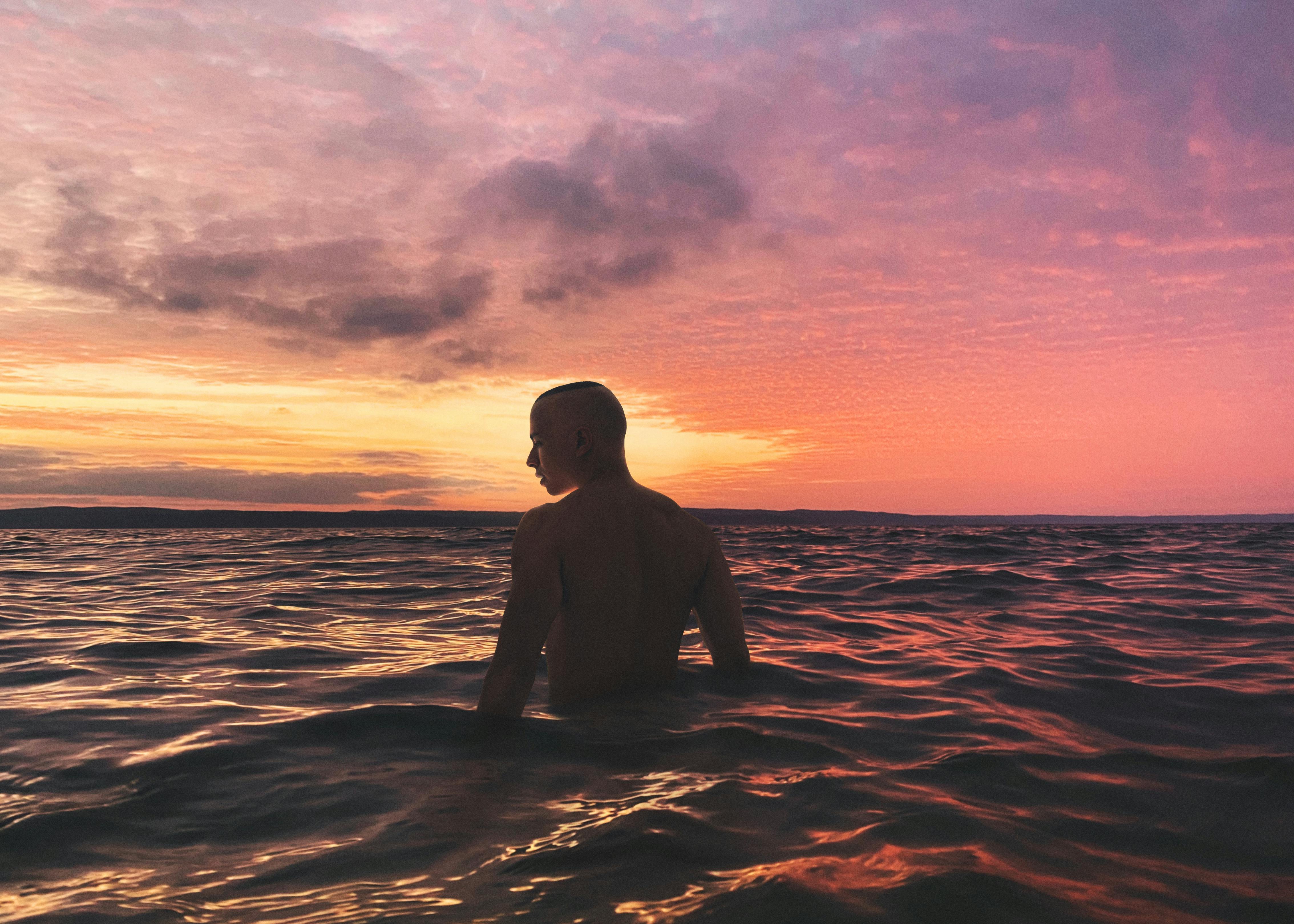 Back View of a Man in the Sea During Pink Sky · Free Stock Photo