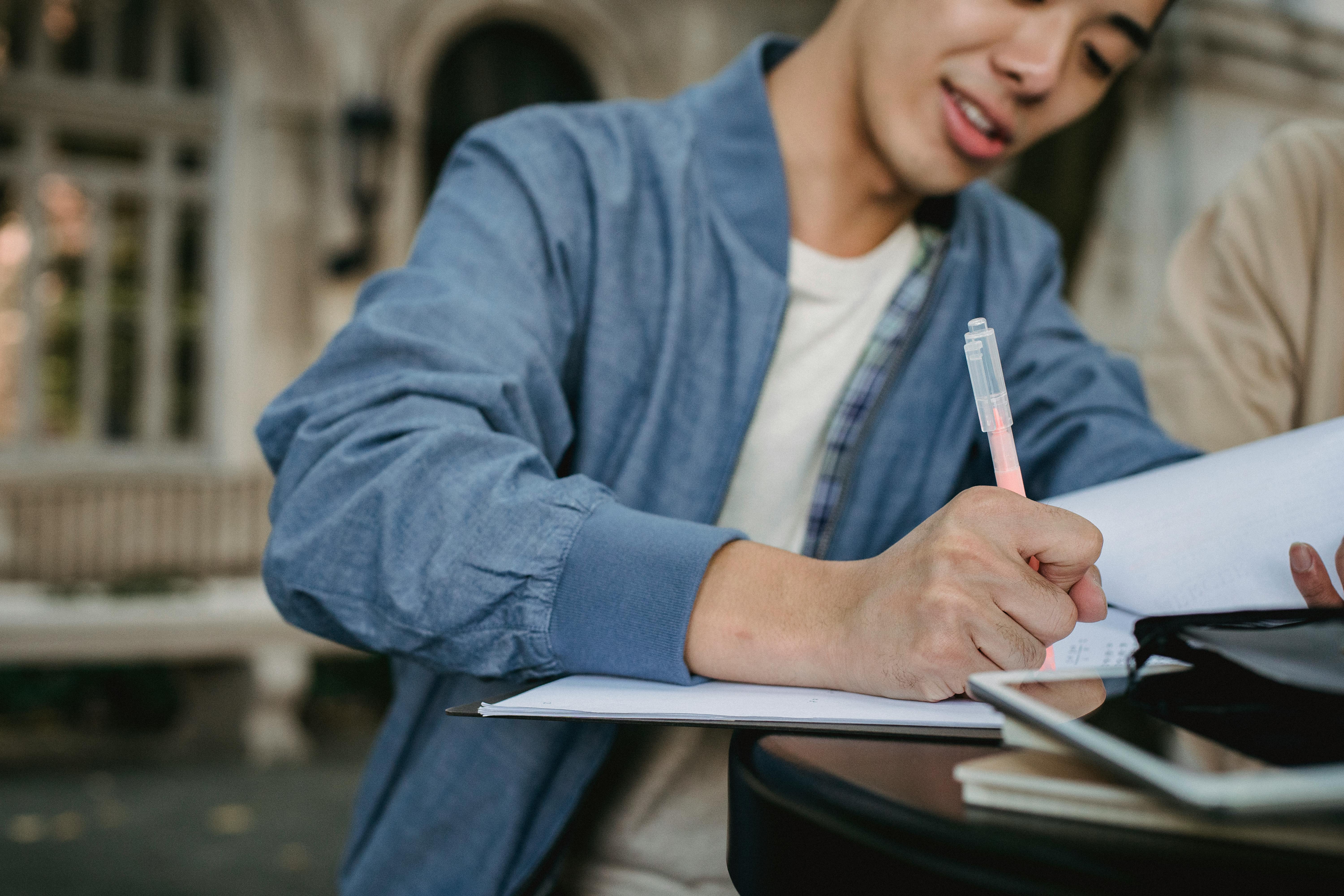 Ethnic student doing homework with classmate in park · Free Stock Photo