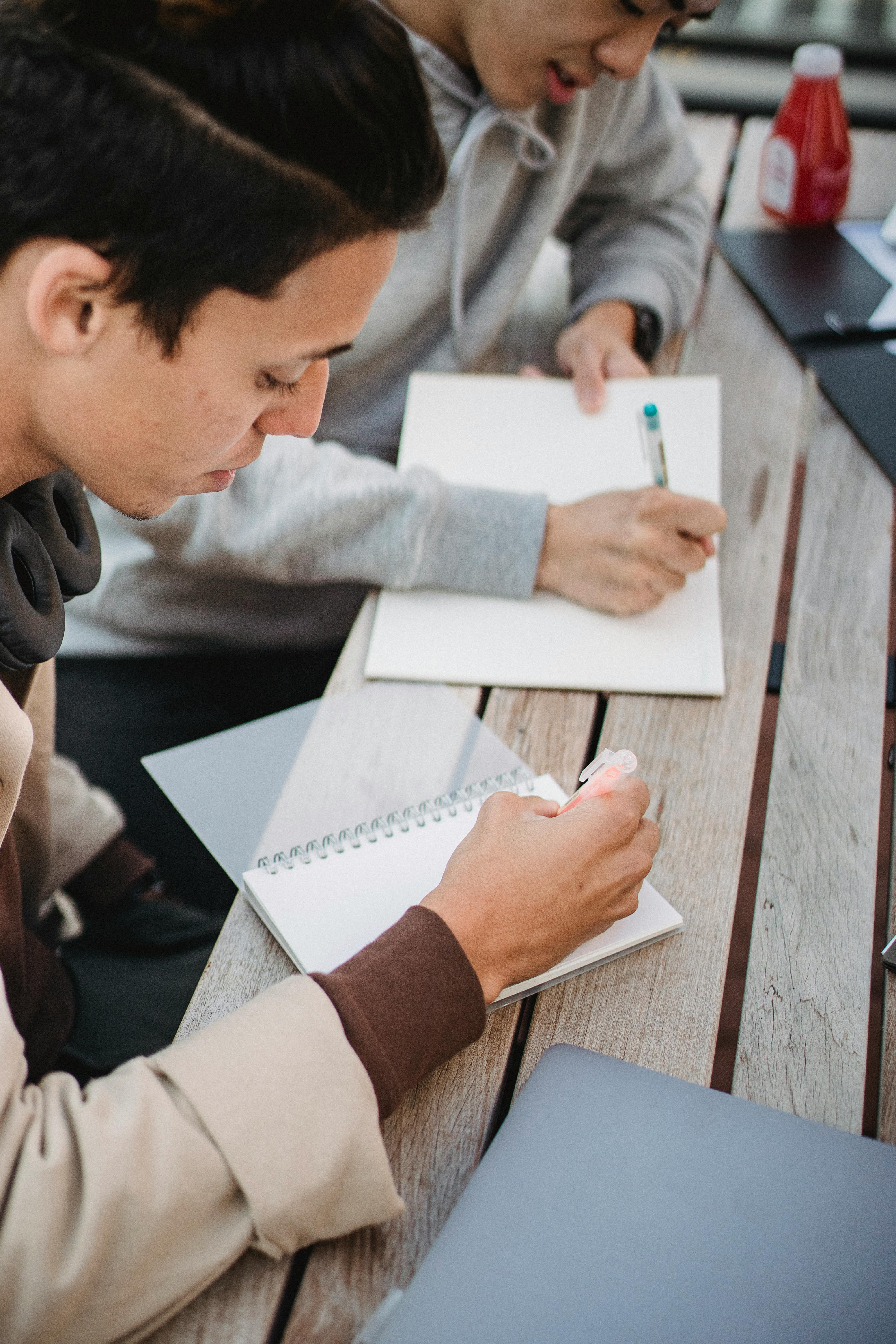Focused students taking notes at table · Free Stock Photo
