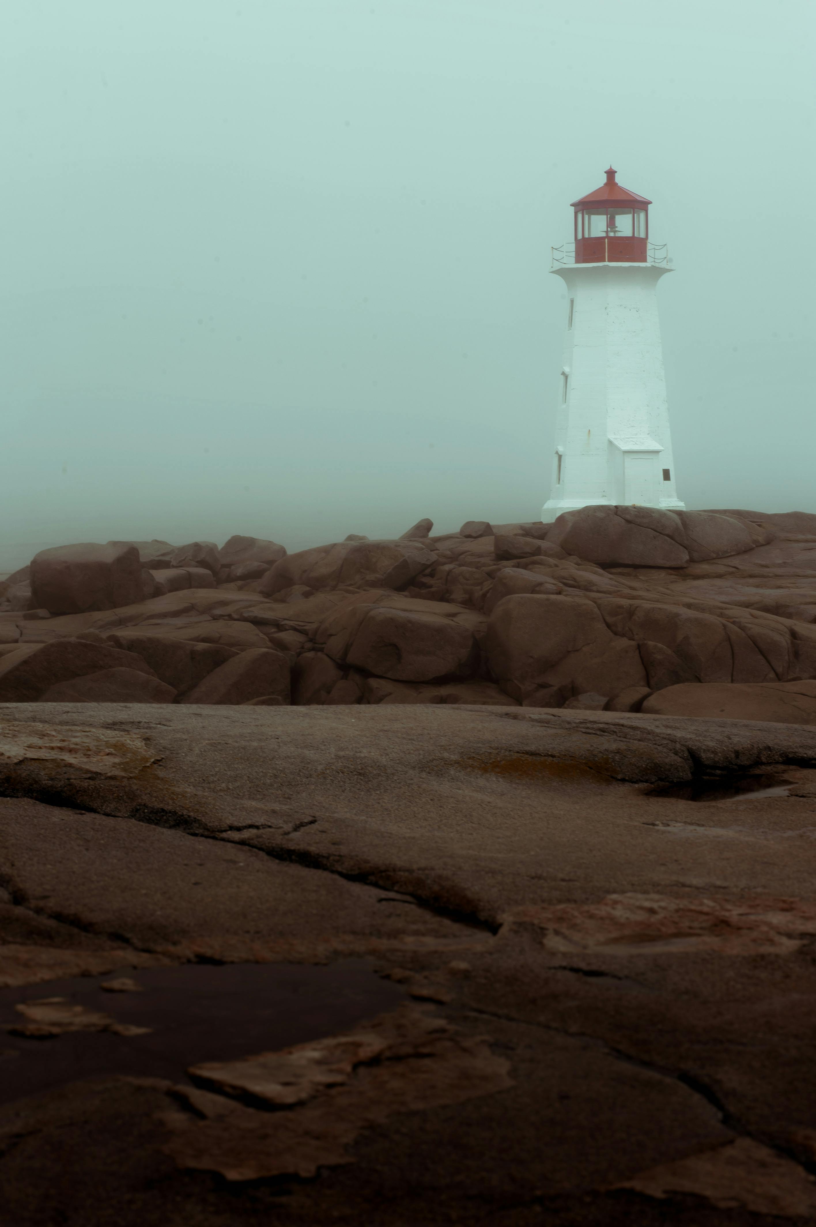 Old stone lighthouse under cloudy sky · Free Stock Photo