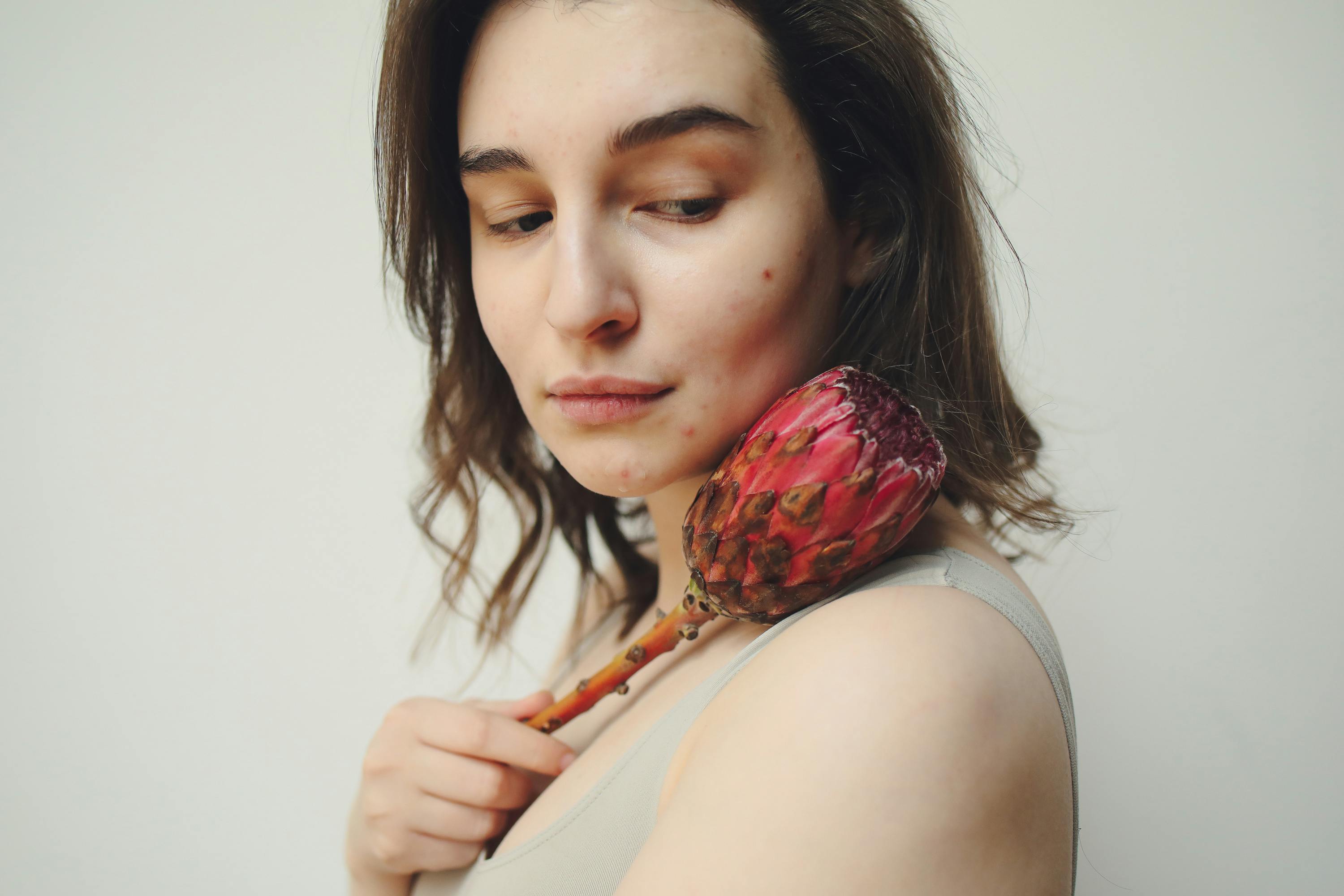 A Woman With Acne Holding a Flower · Free Stock Photo