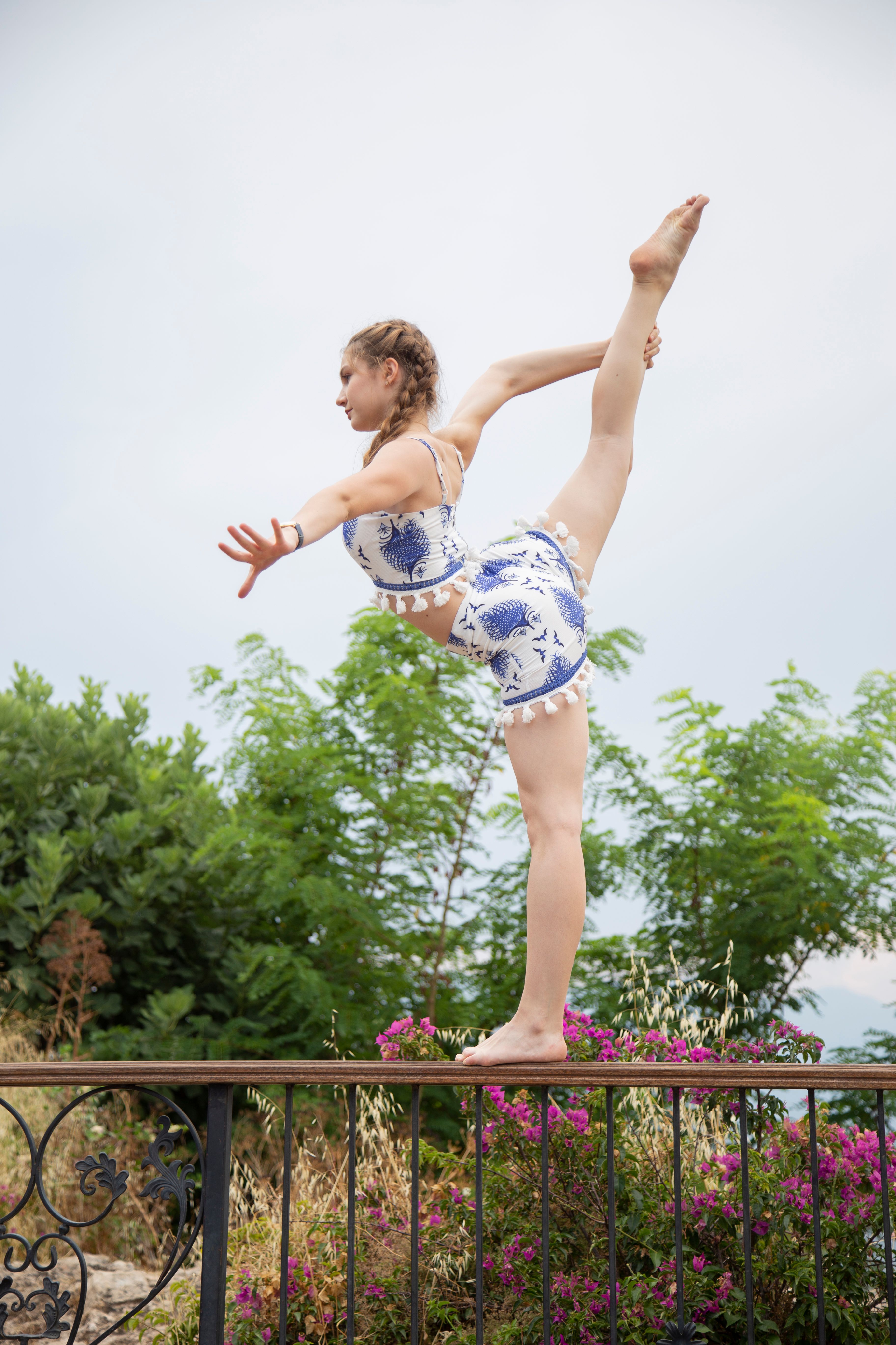 Flexible ballerina standing with raised leg on fence · Free Stock Photo