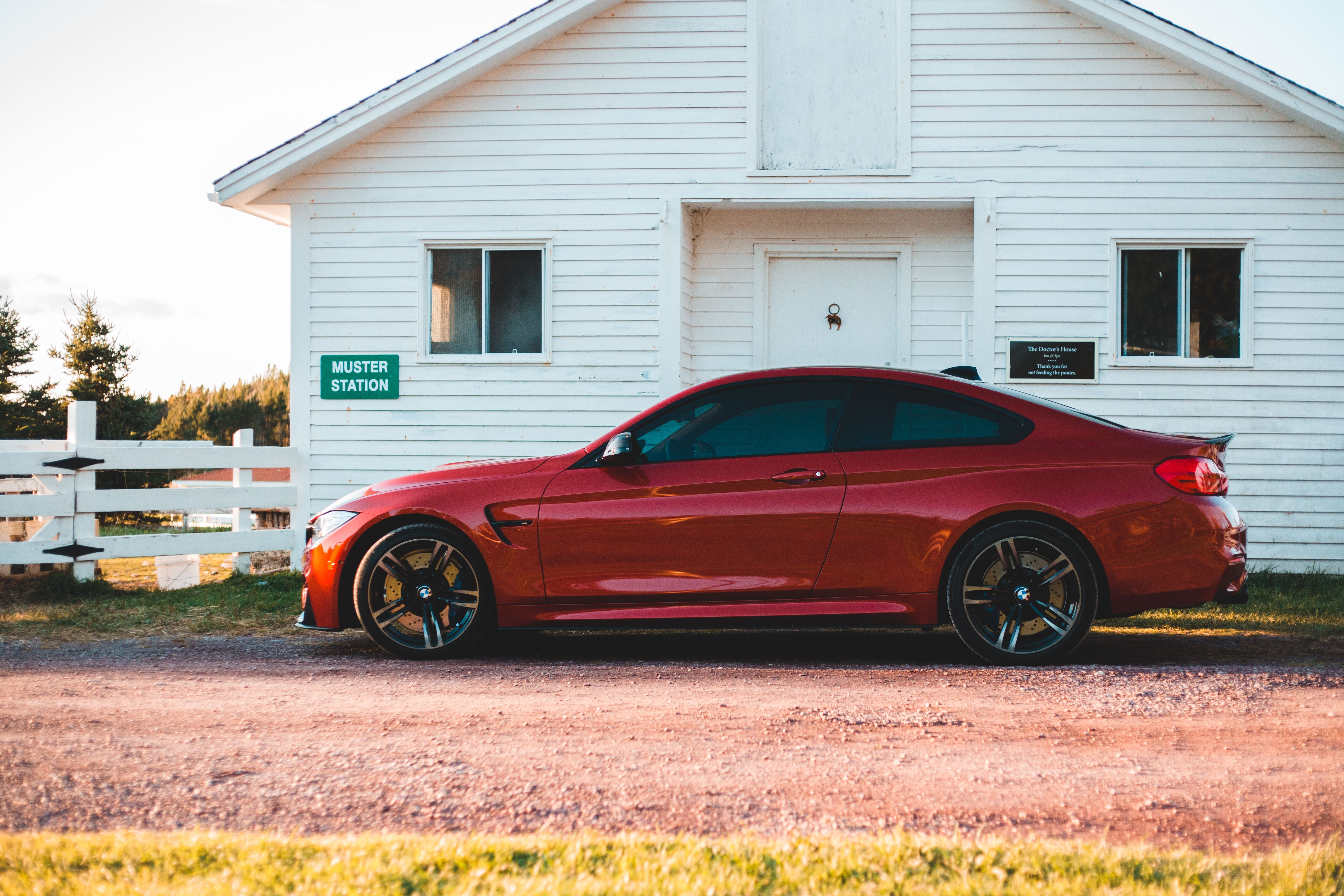 Luxury red car parked near white house in village · Free Stock Photo