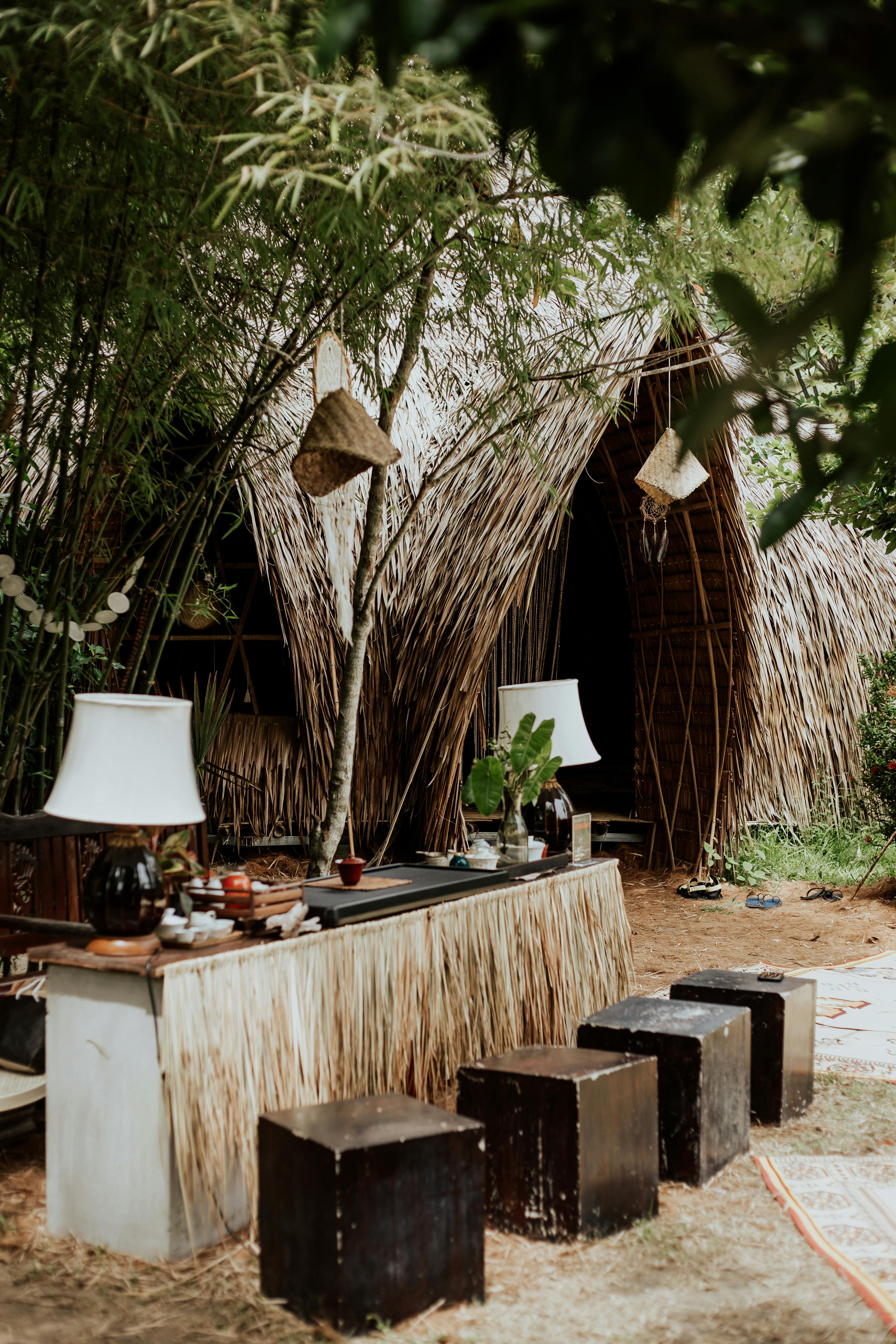 A Hut with Thatched Roof and a Counter with Seats Outside between Green ...
