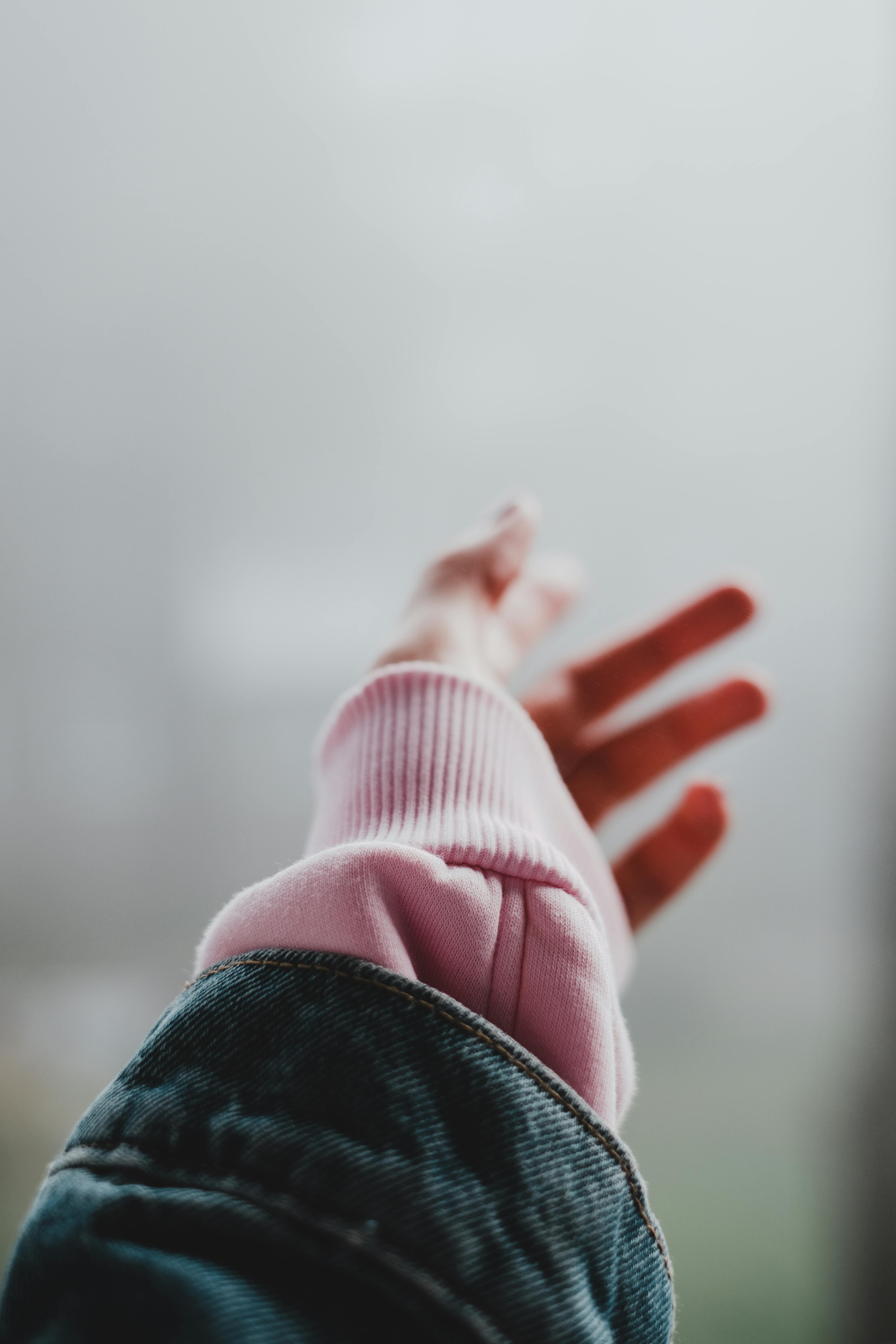 Person in Denim Jacket With Hand Reaching Out · Free Stock Photo