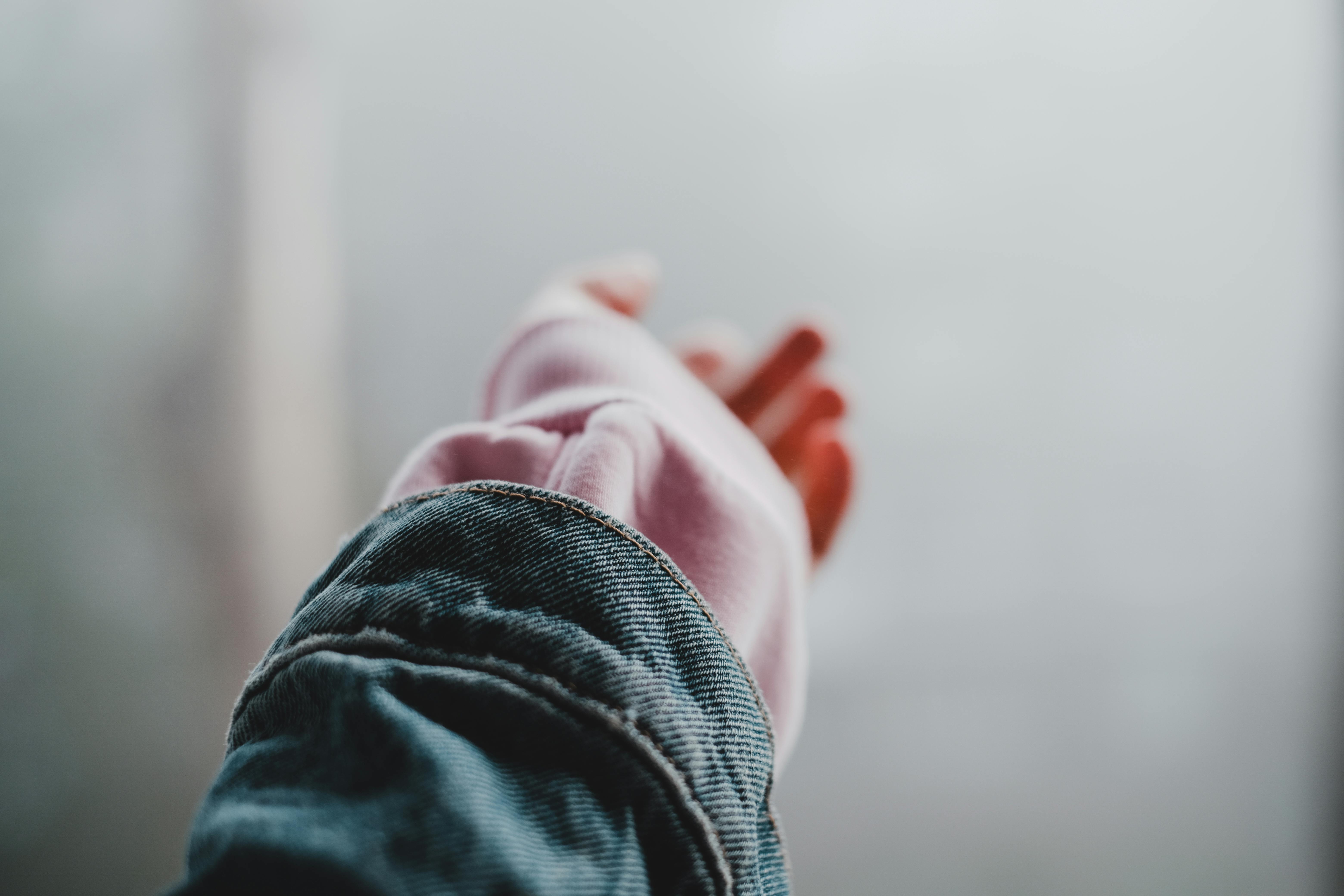 Person in Denim Jacket With Hand Reaching Out · Free Stock Photo