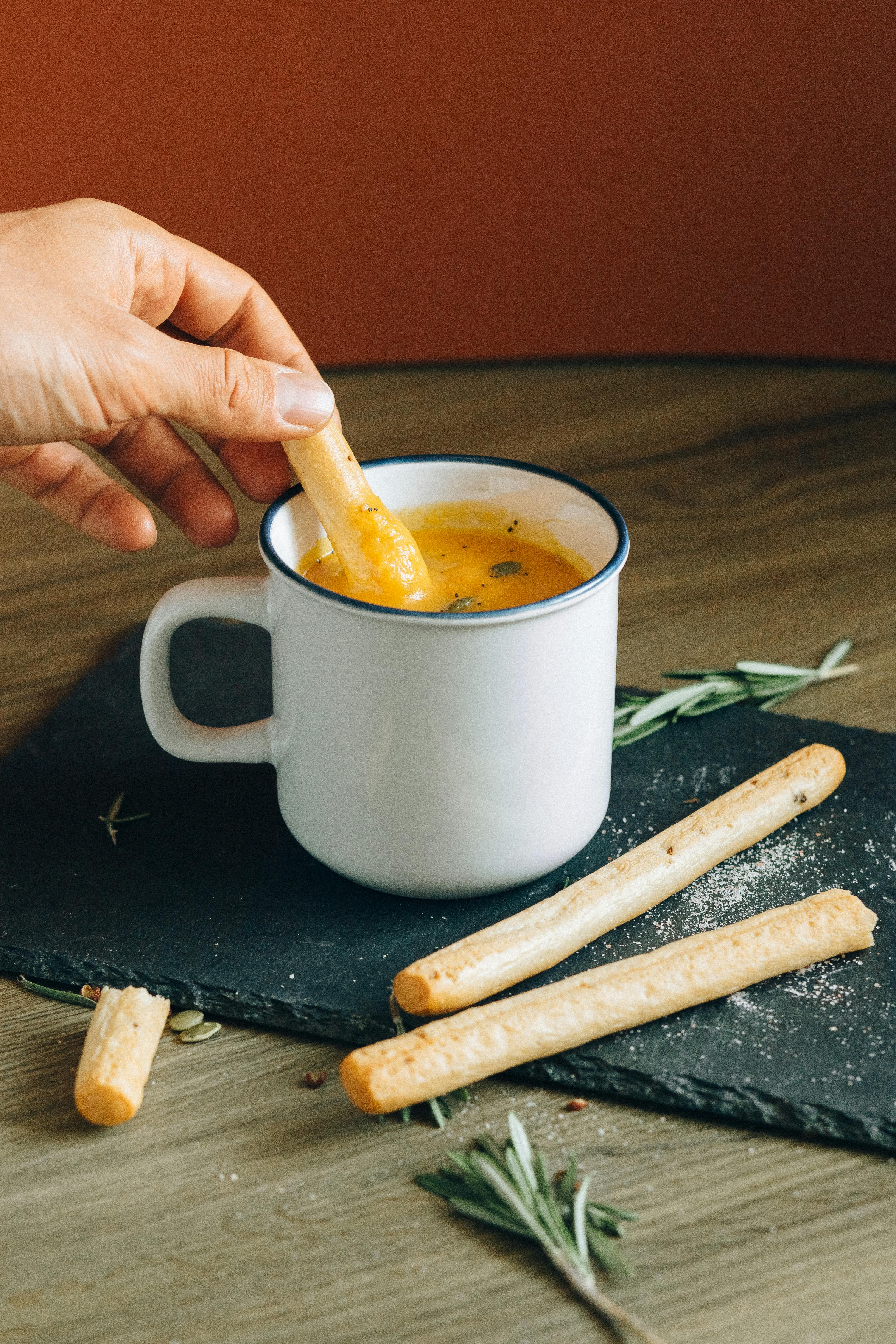 Person Dipping Cracker on Yellow Puree · Free Stock Photo