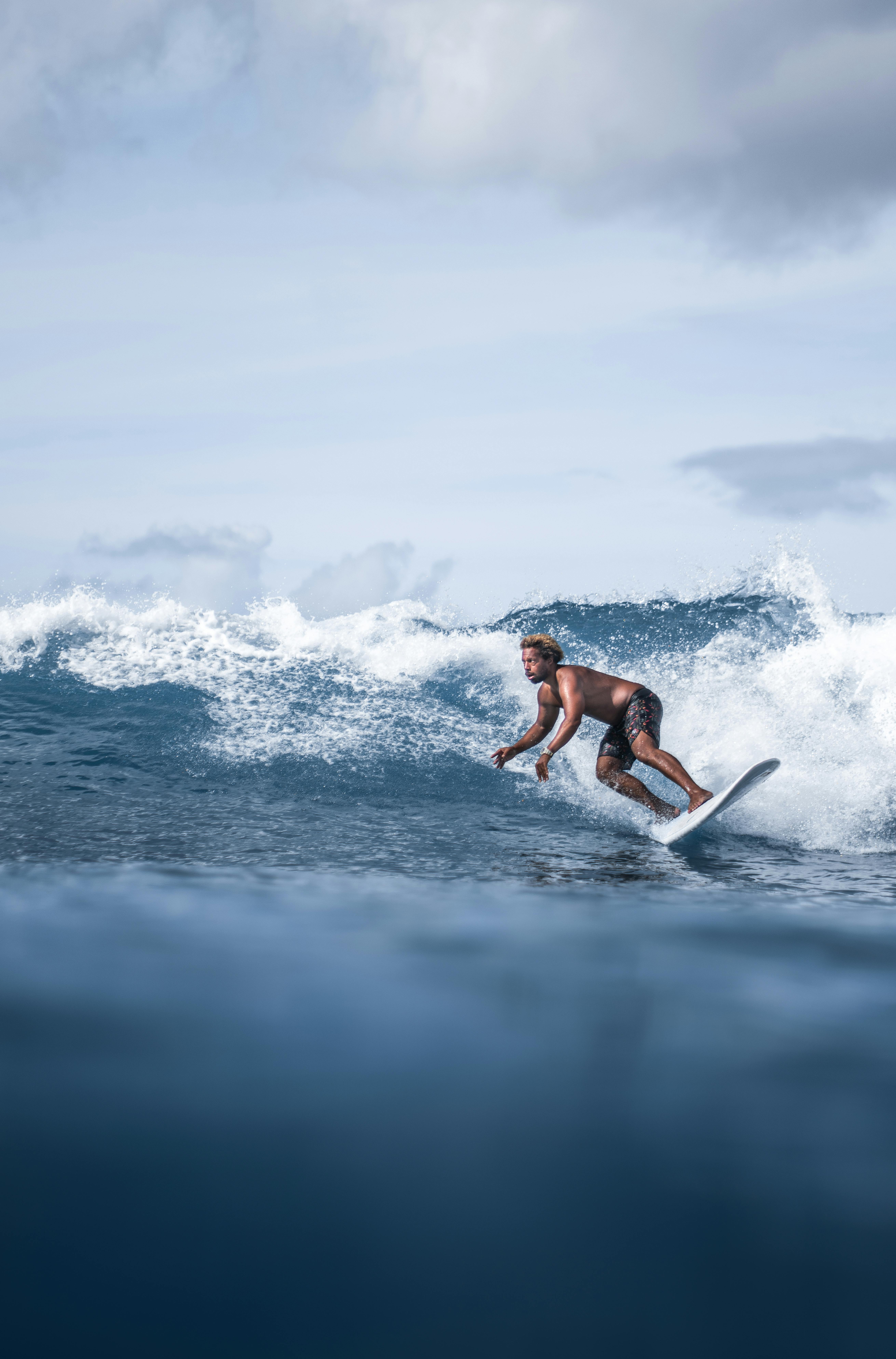 Determined black surfer riding wave on surfboard · Free Stock Photo