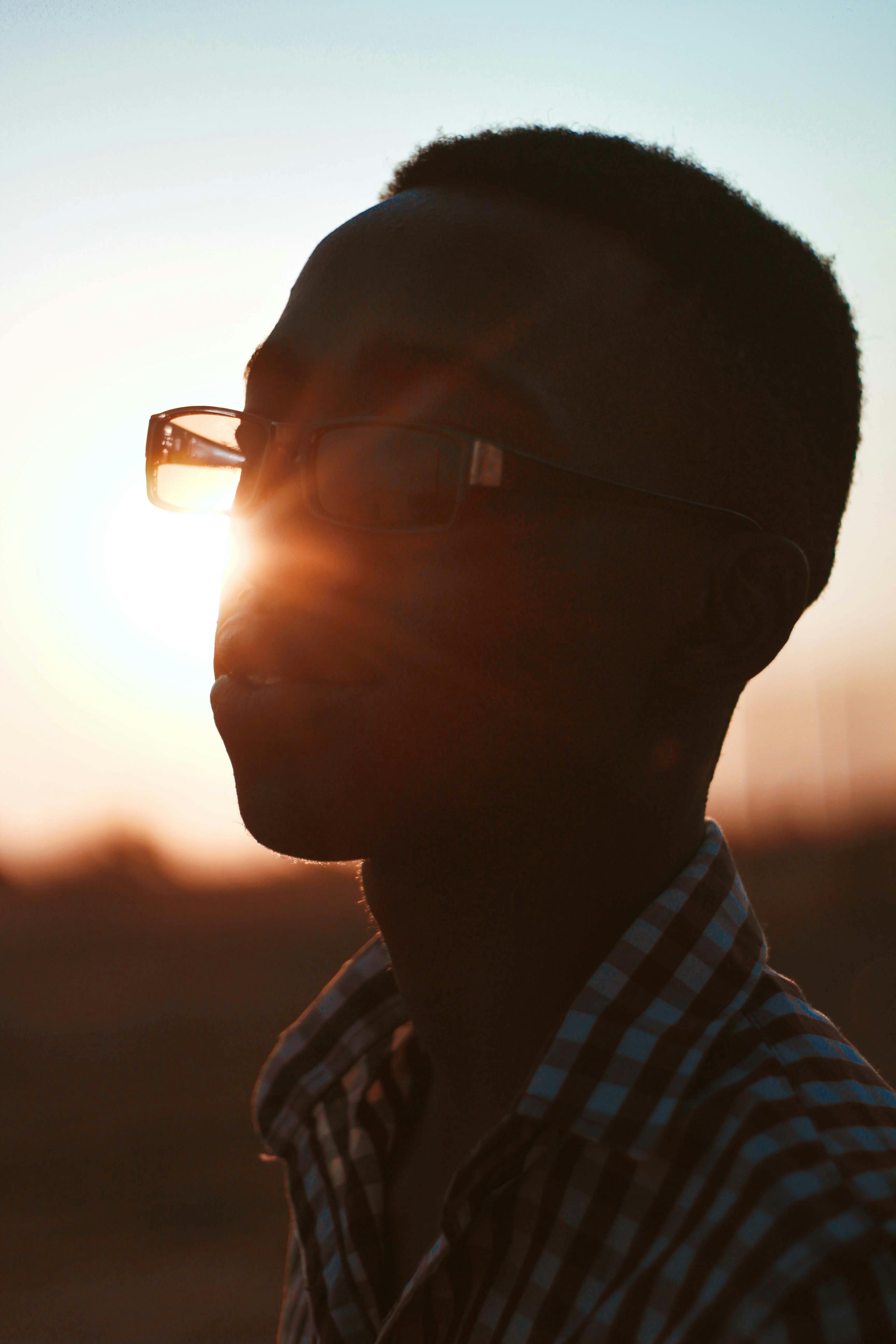 Man covering bright sunlight shining on sunset sky · Free Stock Photo