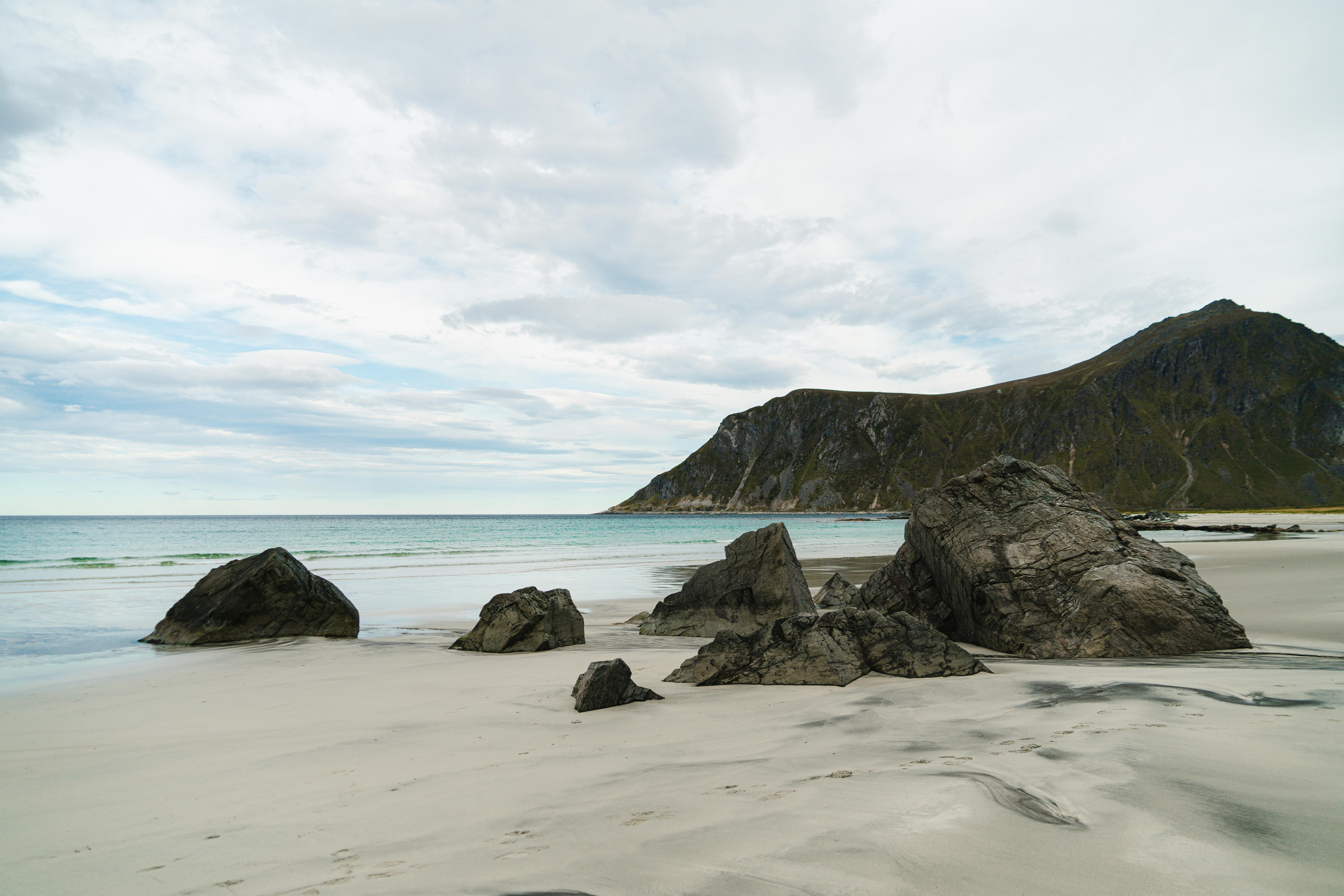 Calm shoreline with rocks and mountains · Free Stock Photo