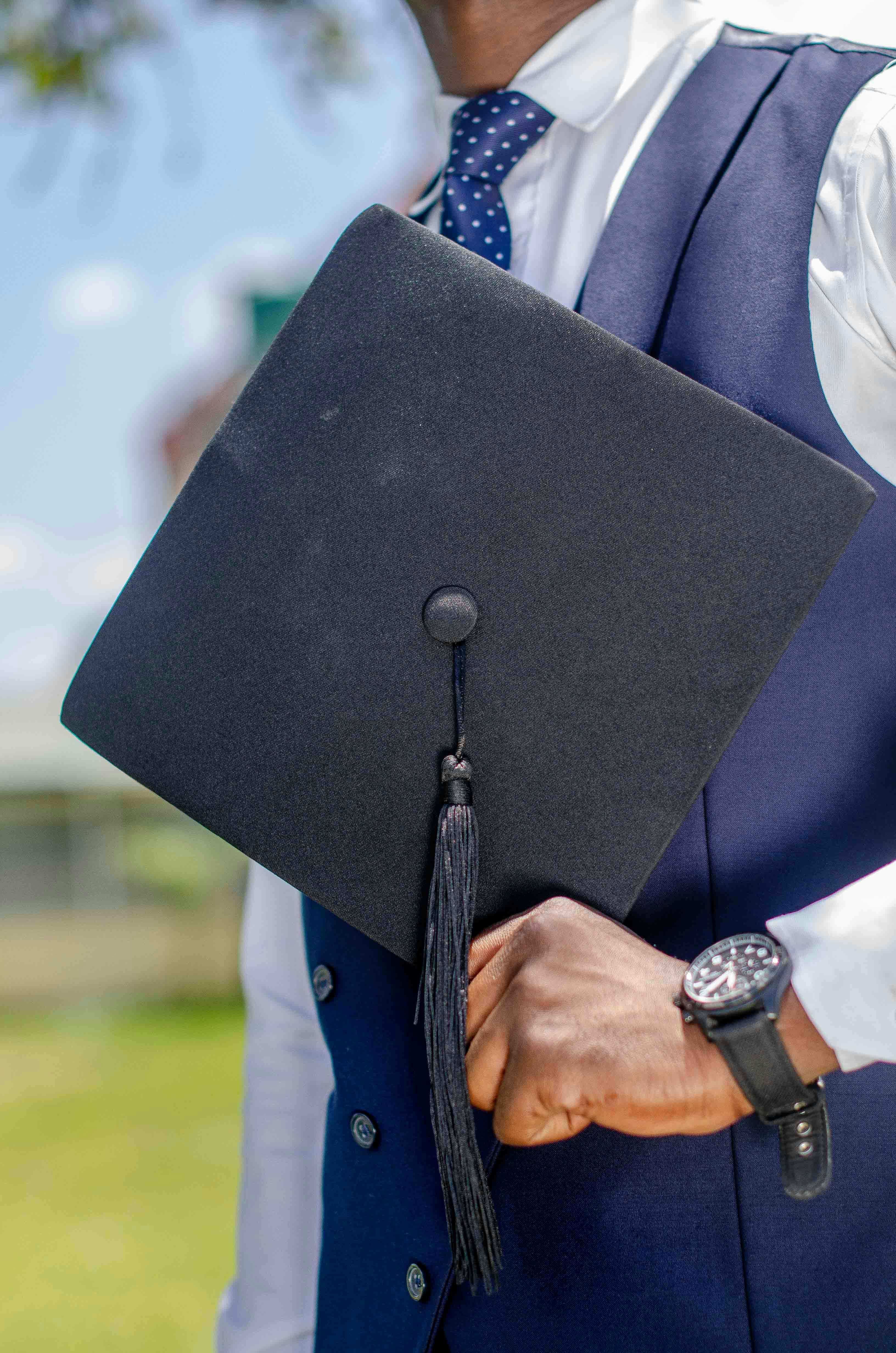 Person in Blue Vest Holding an Academic Cap · Free Stock Photo