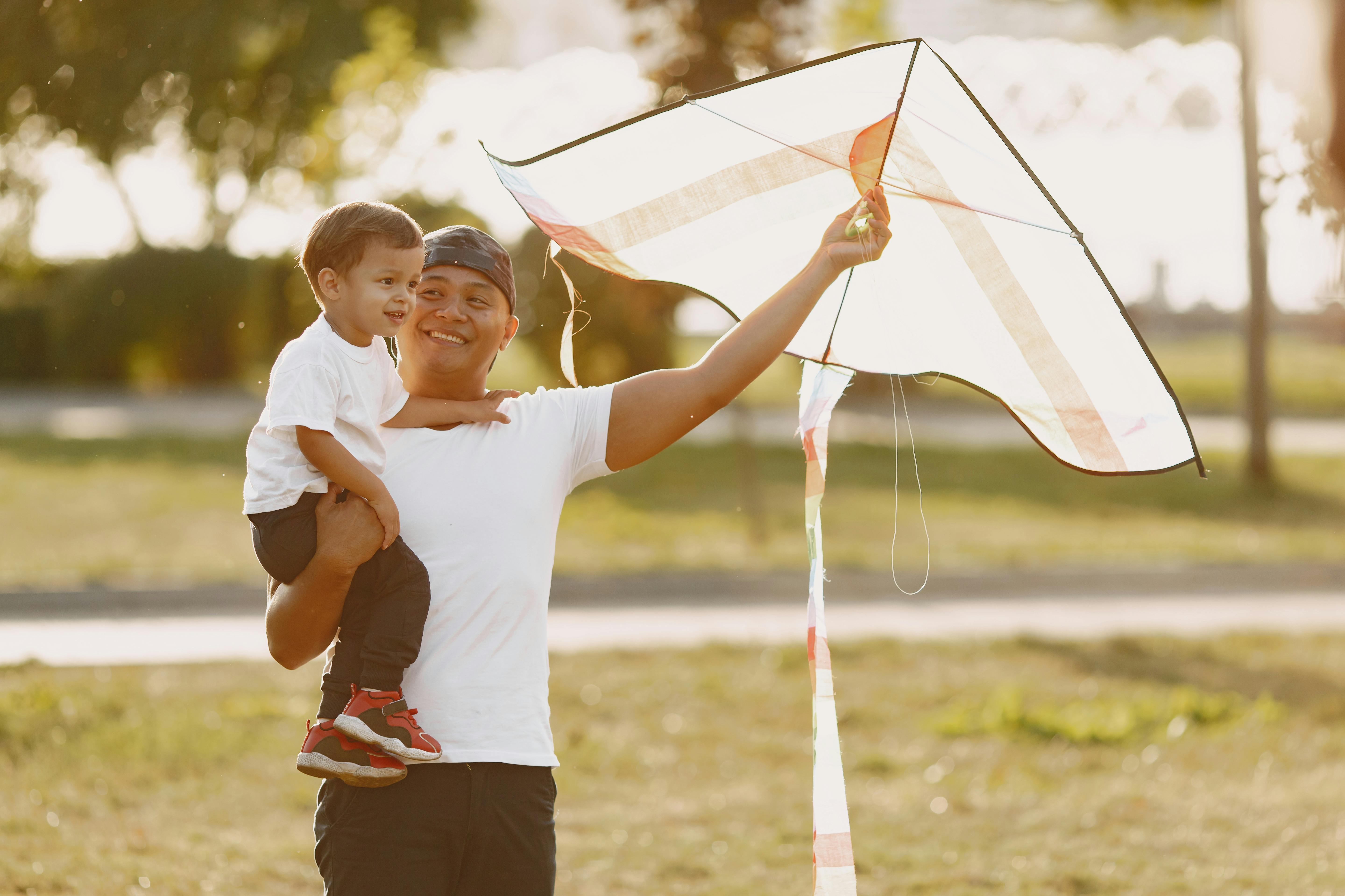 A Father Carrying His Son while Holding a Kite · Free Stock Photo