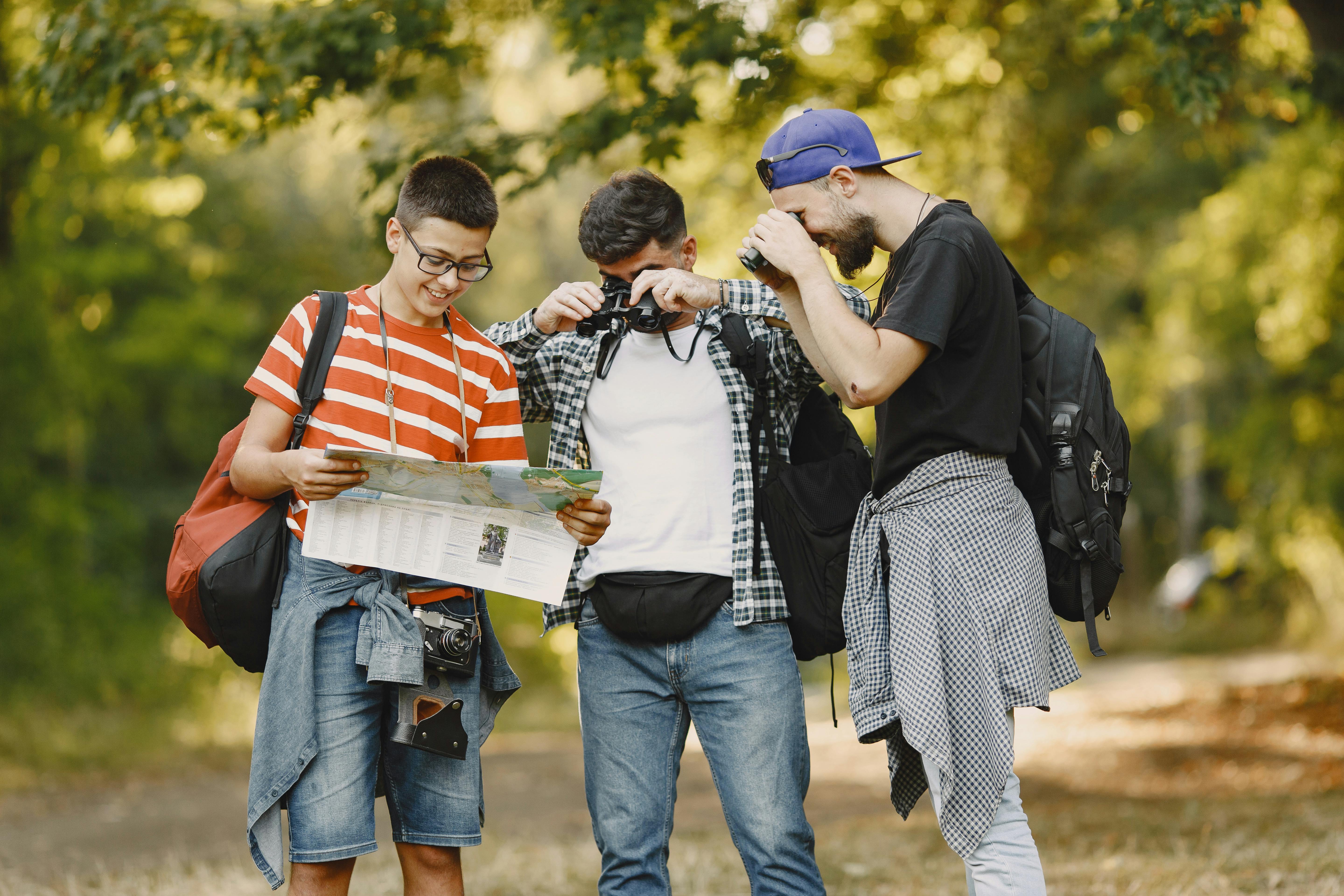 Three Young Hikers Looking at Map · Free Stock Photo