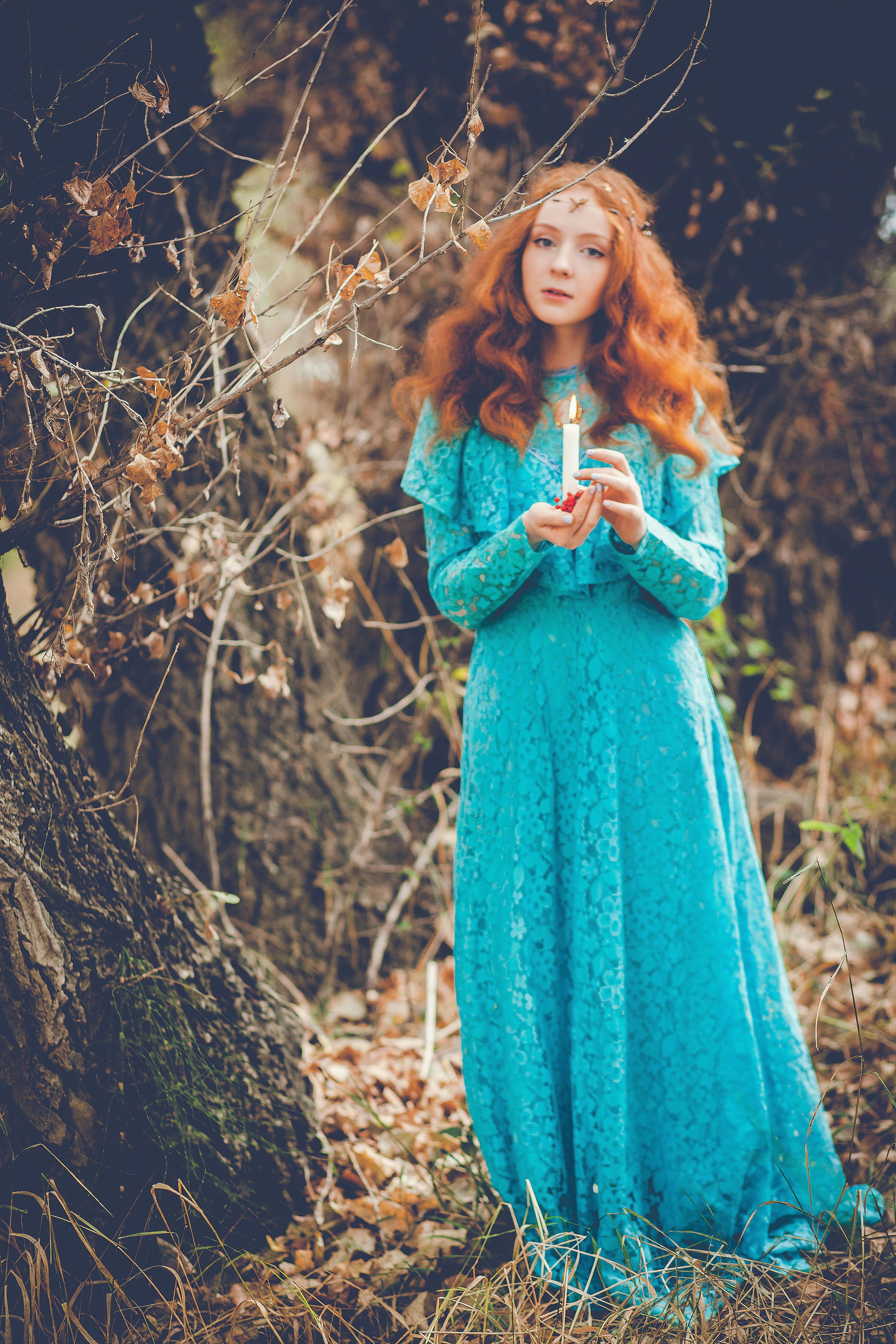Charming woman in historical dress with candle in forest · Free Stock Photo
