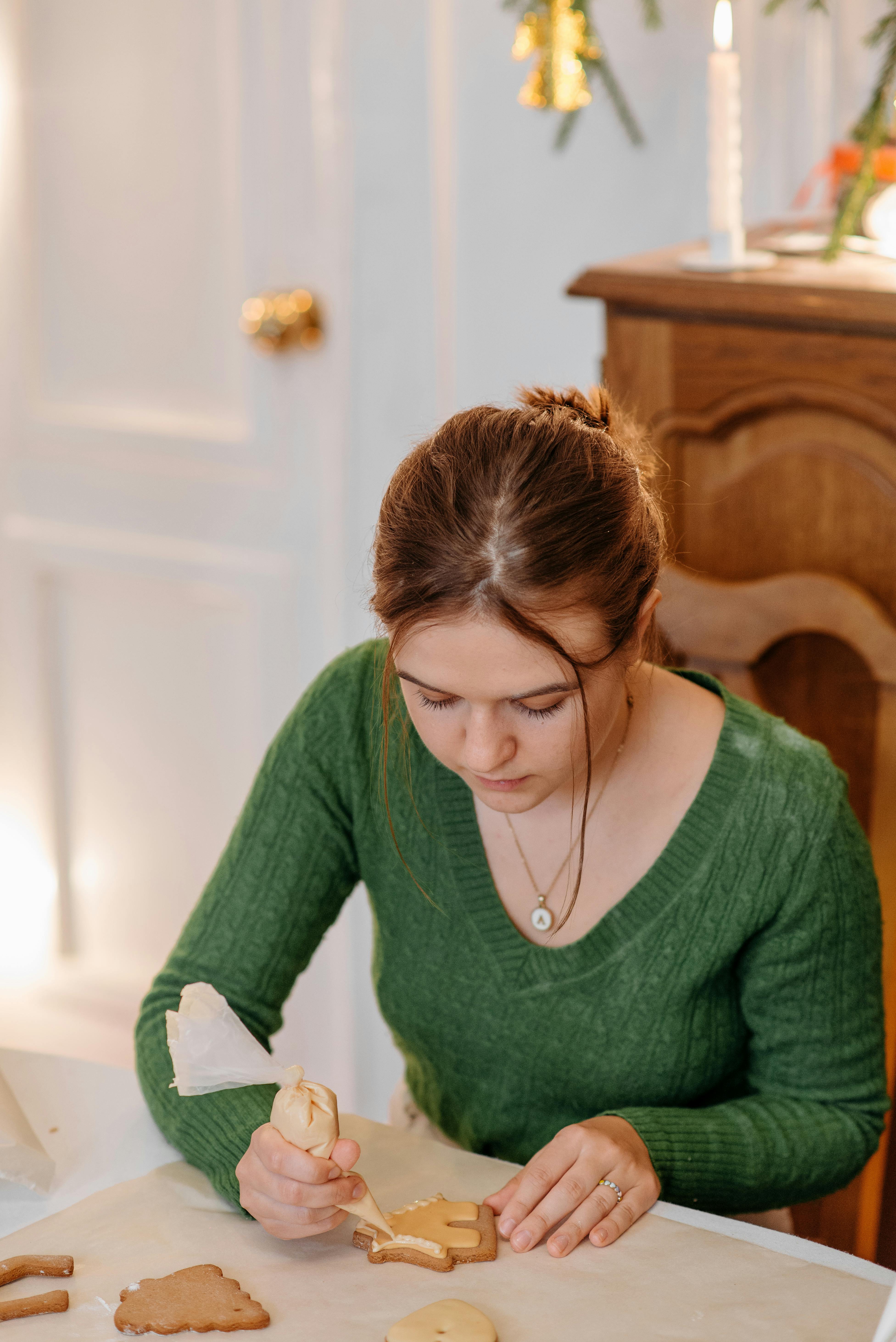 Woman in Green Cardigan Decorating A Cookie · Free Stock Photo