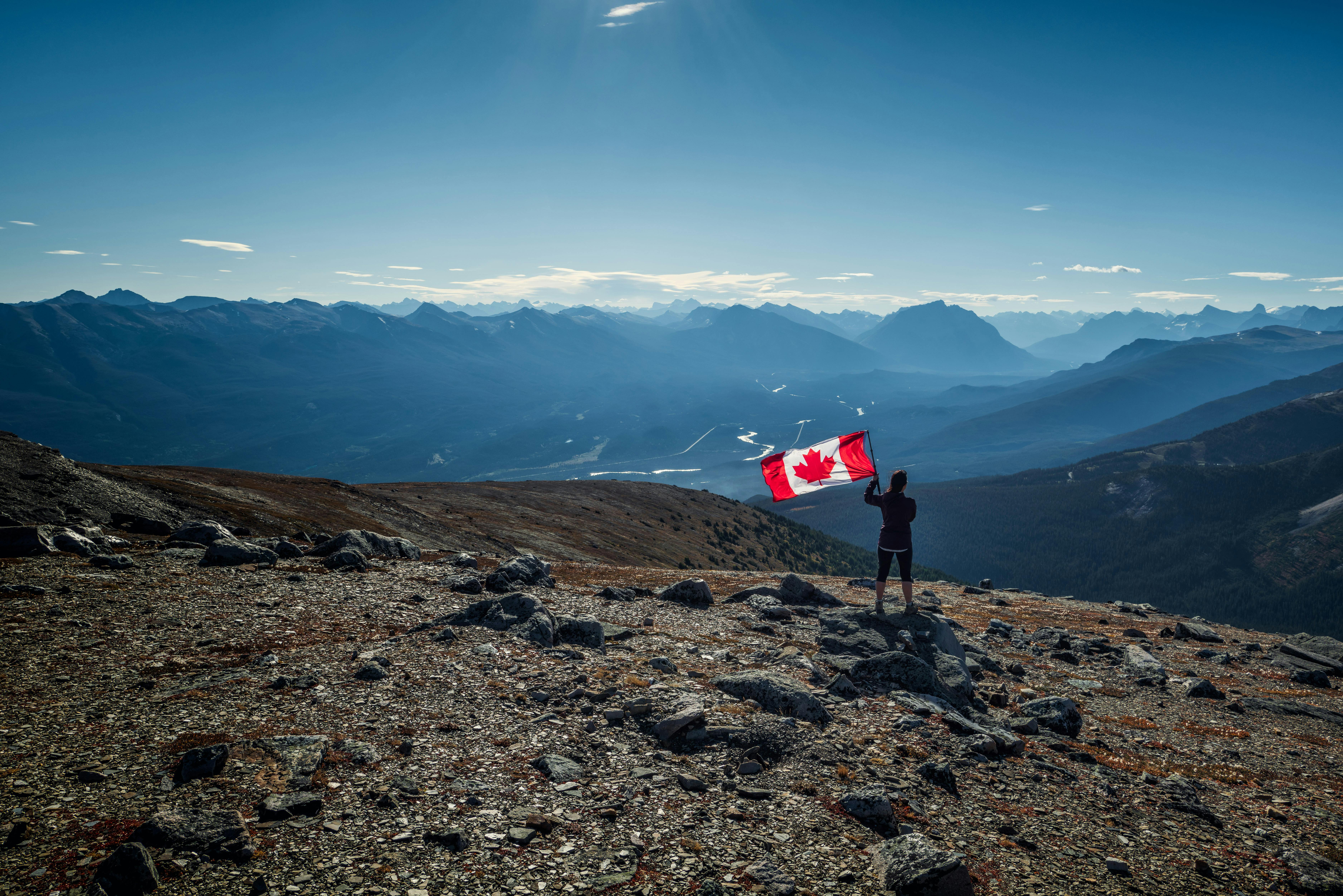 A Person Holding a Canadian Flag on the Mountain Top · Free Stock Photo