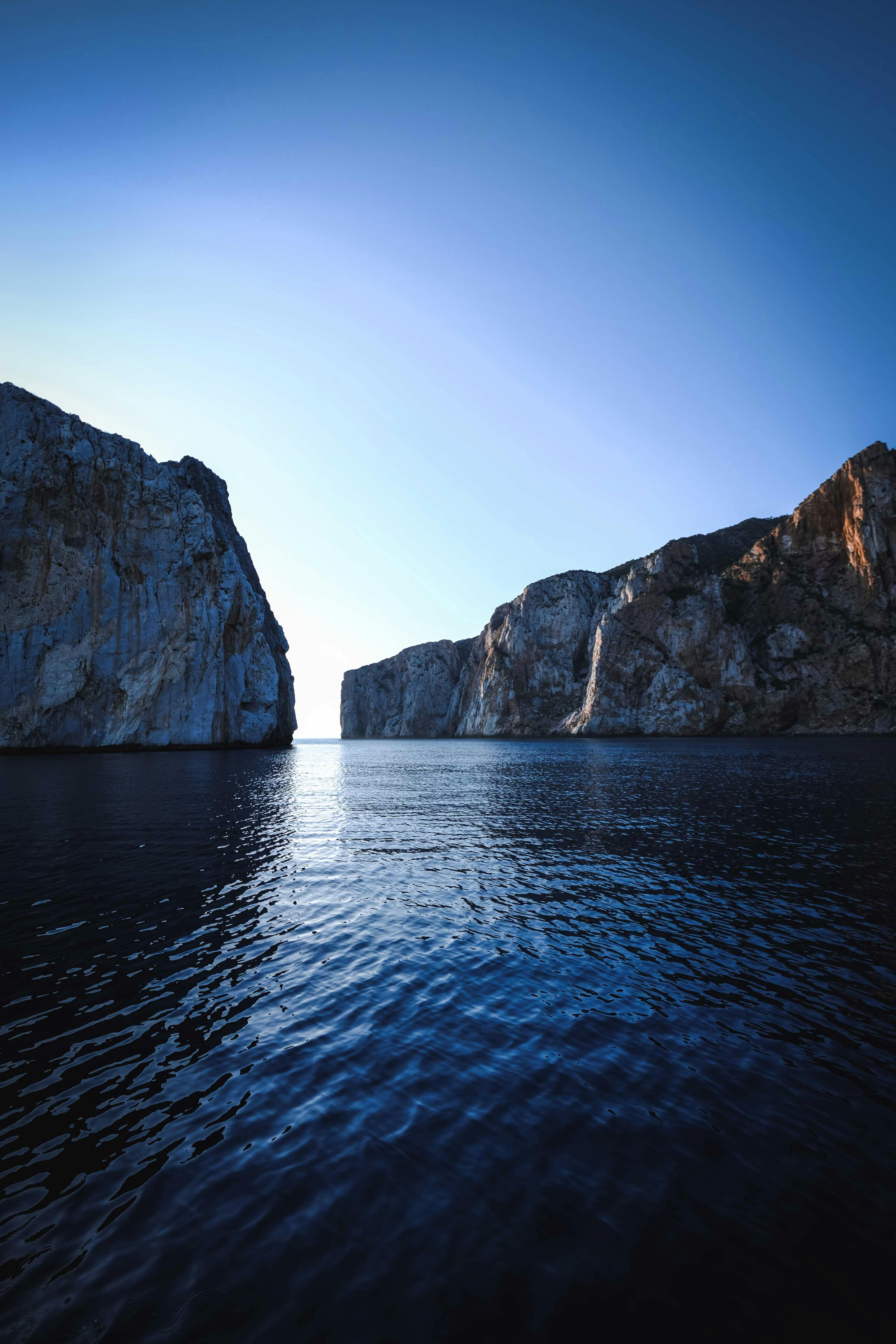 Sea between high cliffs under light sky · Free Stock Photo