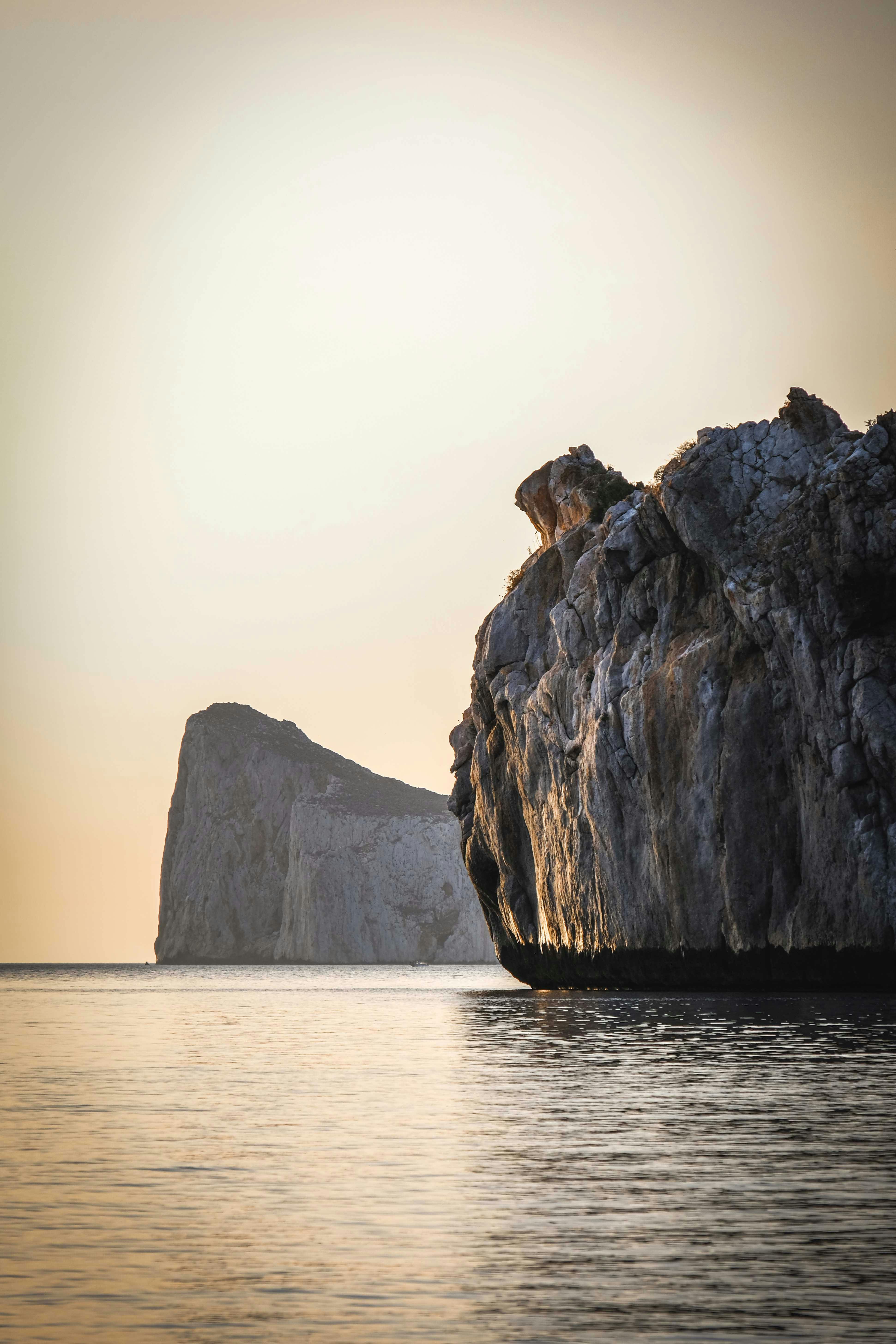 Rough rocks in shiny ocean at sundown · Free Stock Photo