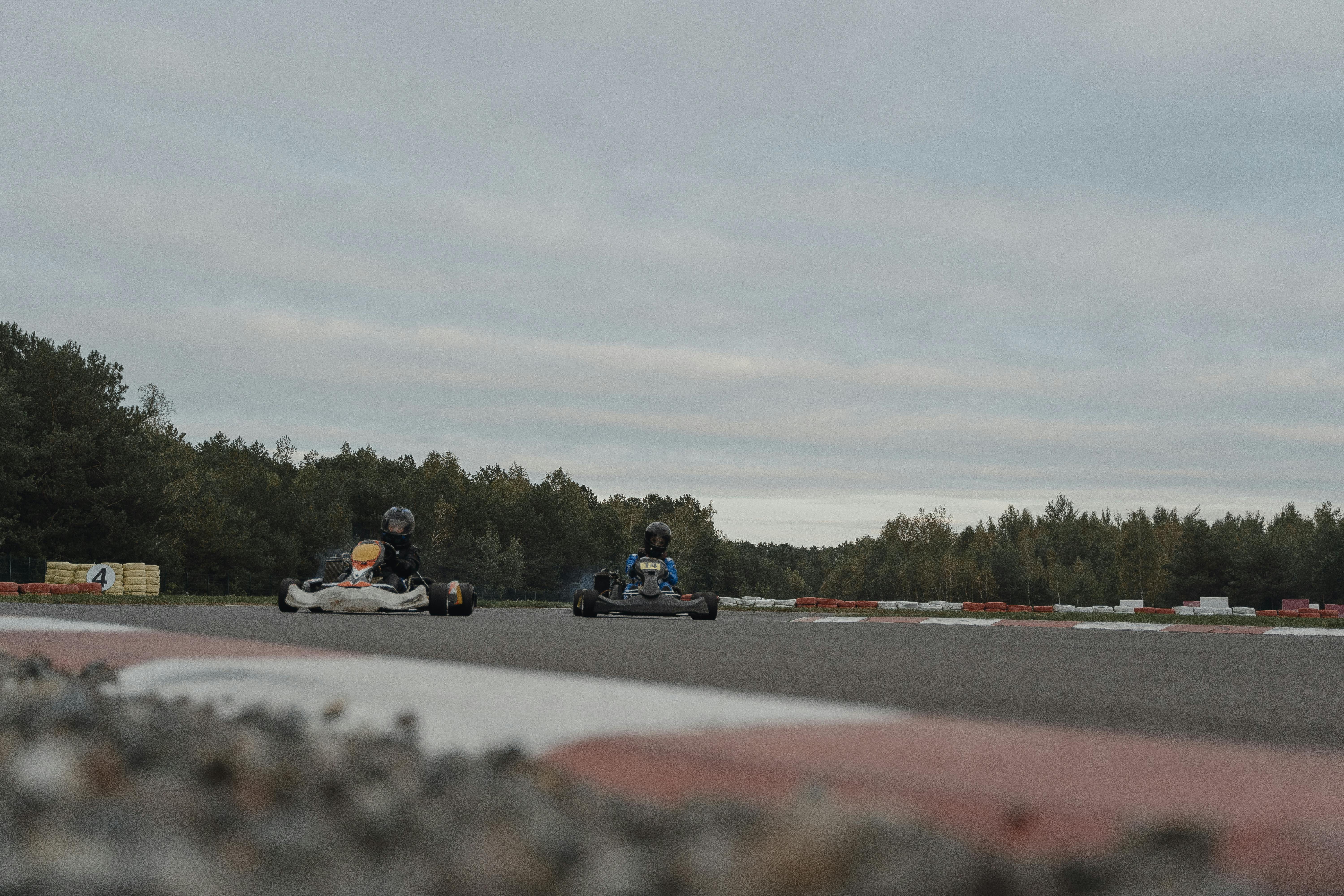 Low-Angle Shot of People Driving Go-Karts in Racetrack · Free Stock Photo