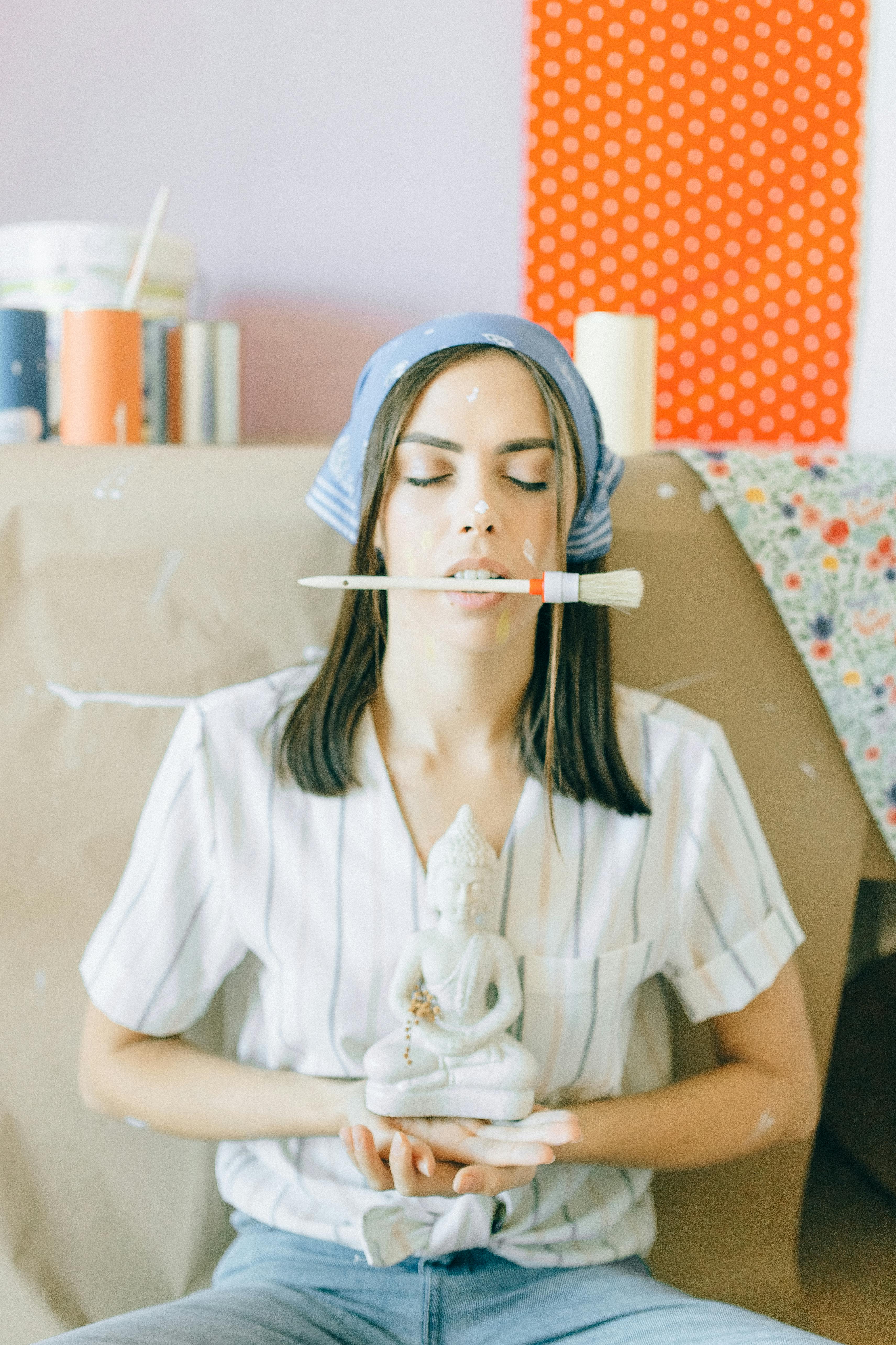 Woman in Striped Shirt Meditating while Biting on a Paint Brush · Free ...
